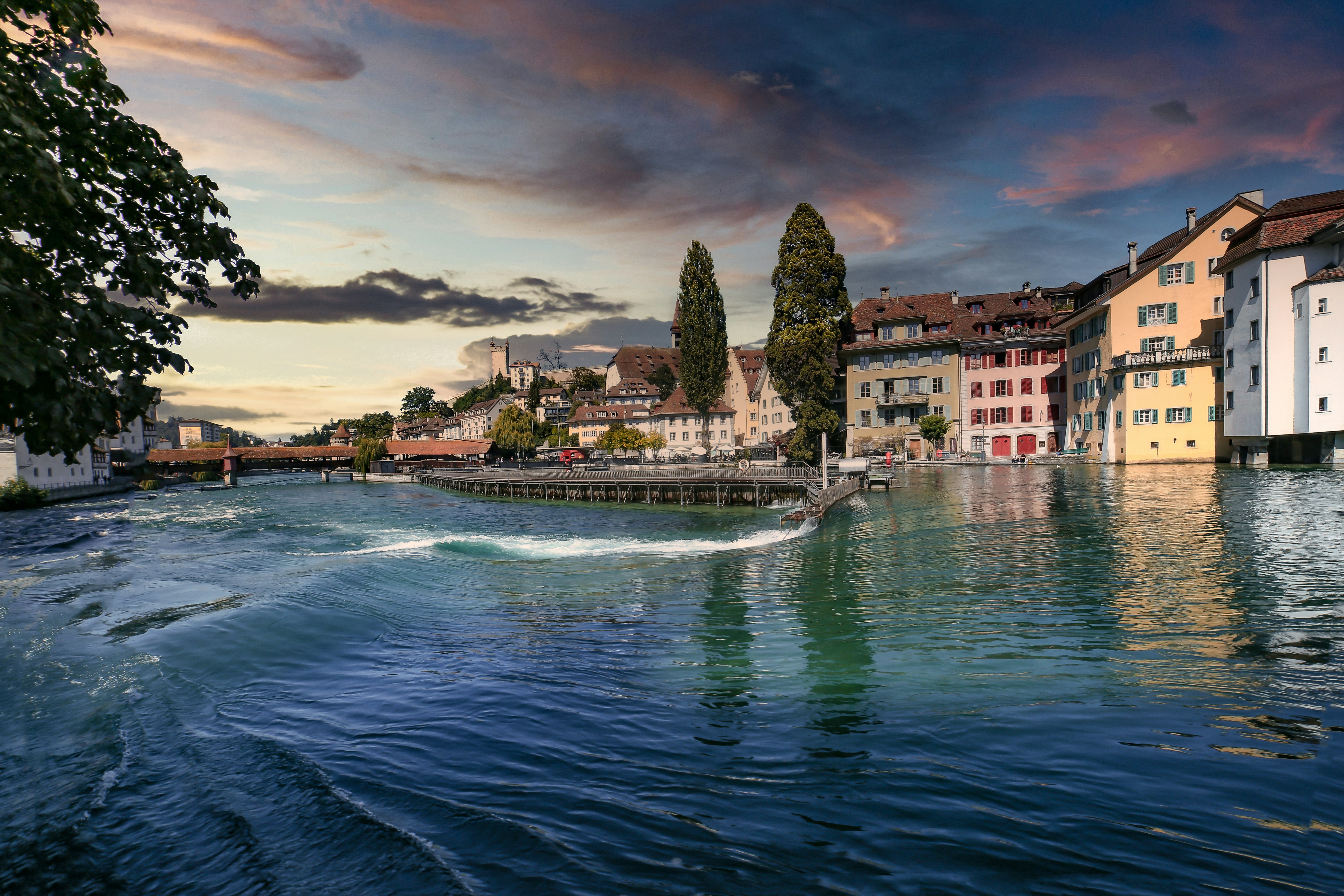 Tranquil river reflecting colorful buildings under a vibrant sunset sky.