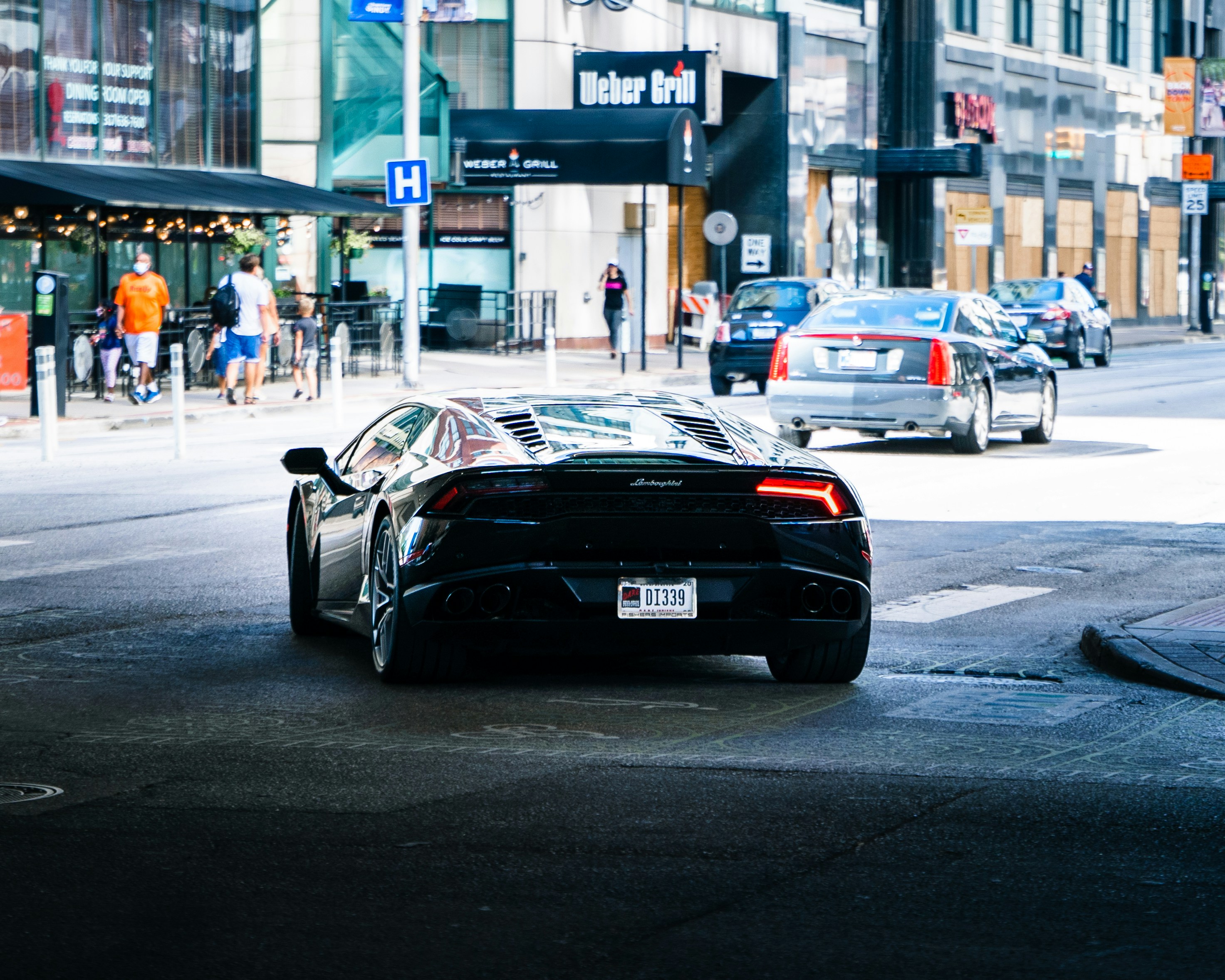 Black Porsche 911 cruising through a busy city street during the day.