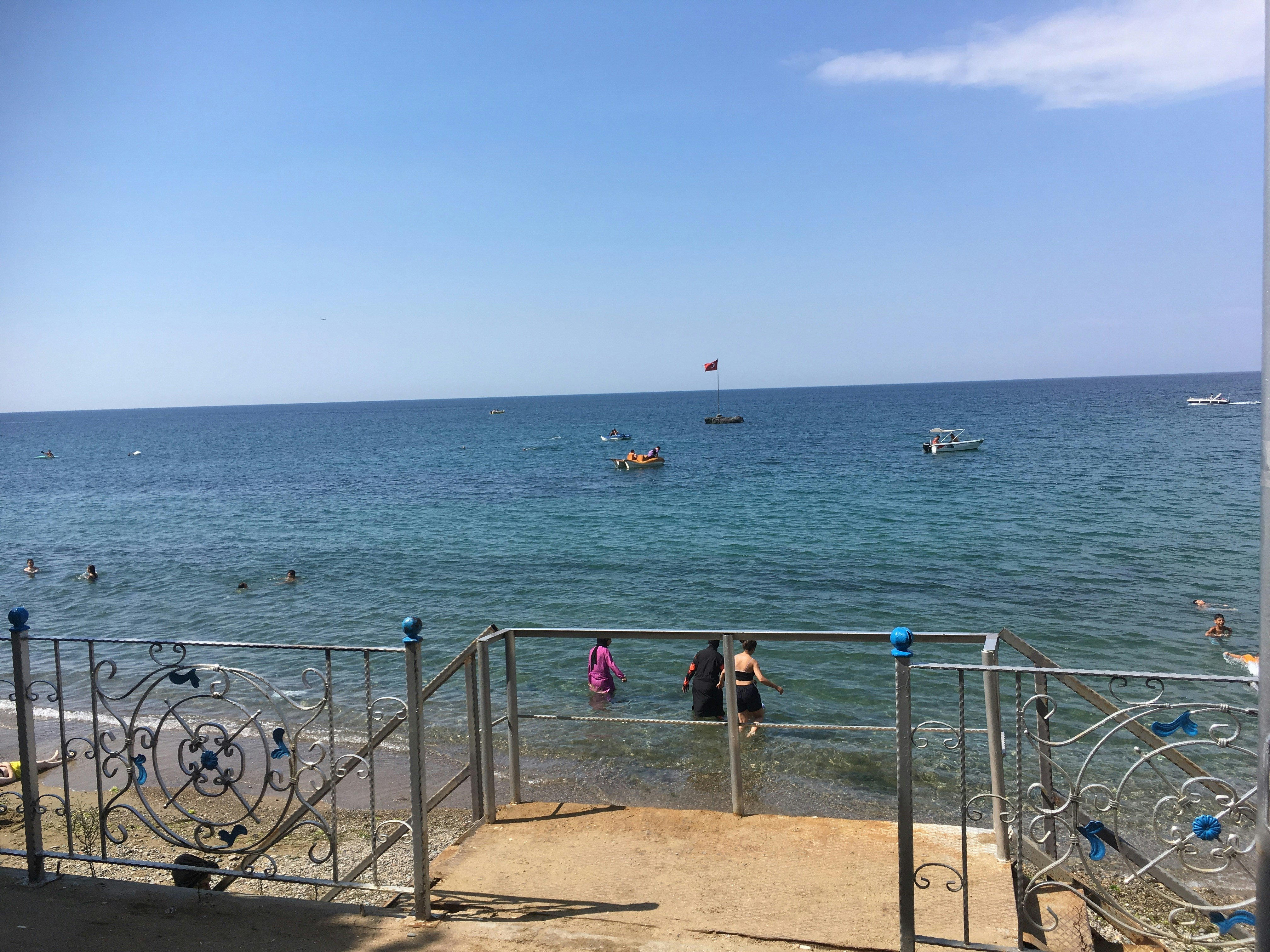 Sunlit Railings and Quiet Blue: Beachgoers at the Water's Edge