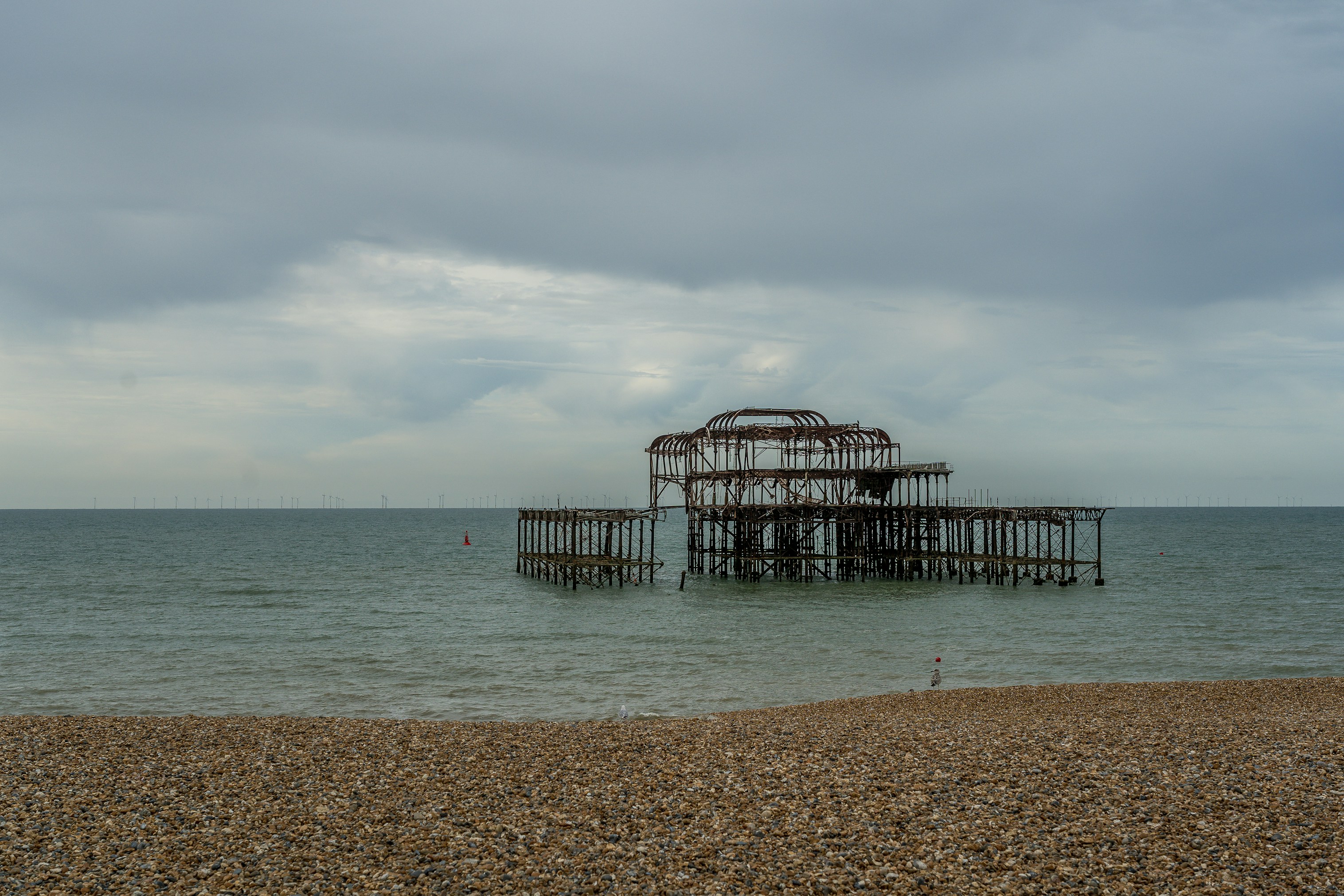 Steel remains of Brighton's West Pier stand against a muted sea and sky backdrop.