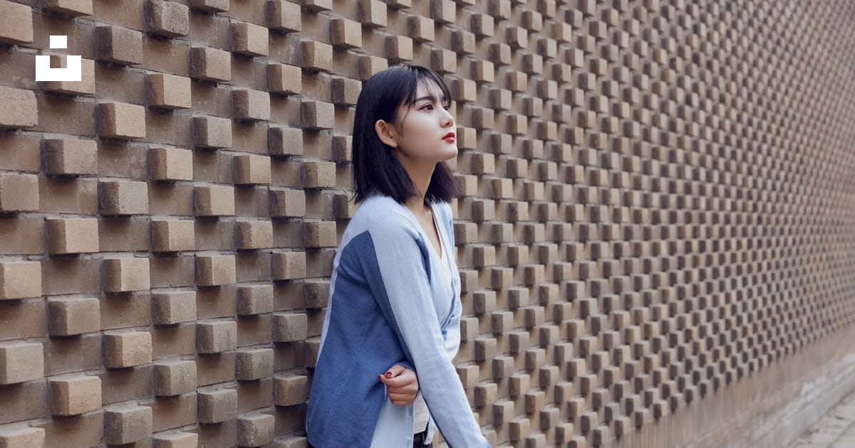 파란색 블레이저와 검은 바지를 입은 여자가 갈색 벽돌 벽 옆에 서 있다 사진 Unsplash의 무료 회색 이미지