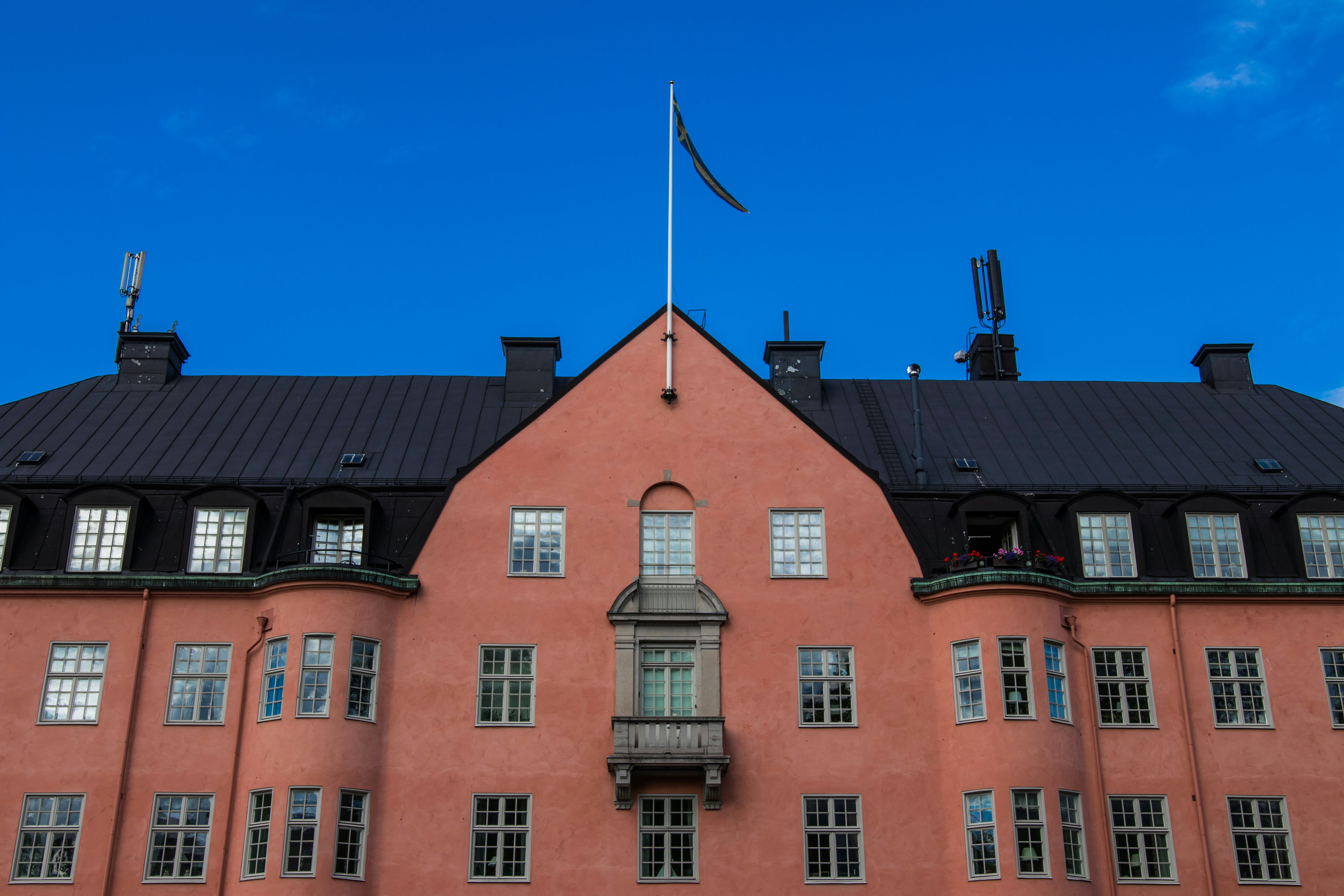 Flag at the Apex: A Central Gable Dominates a Sunlit Brick Campus