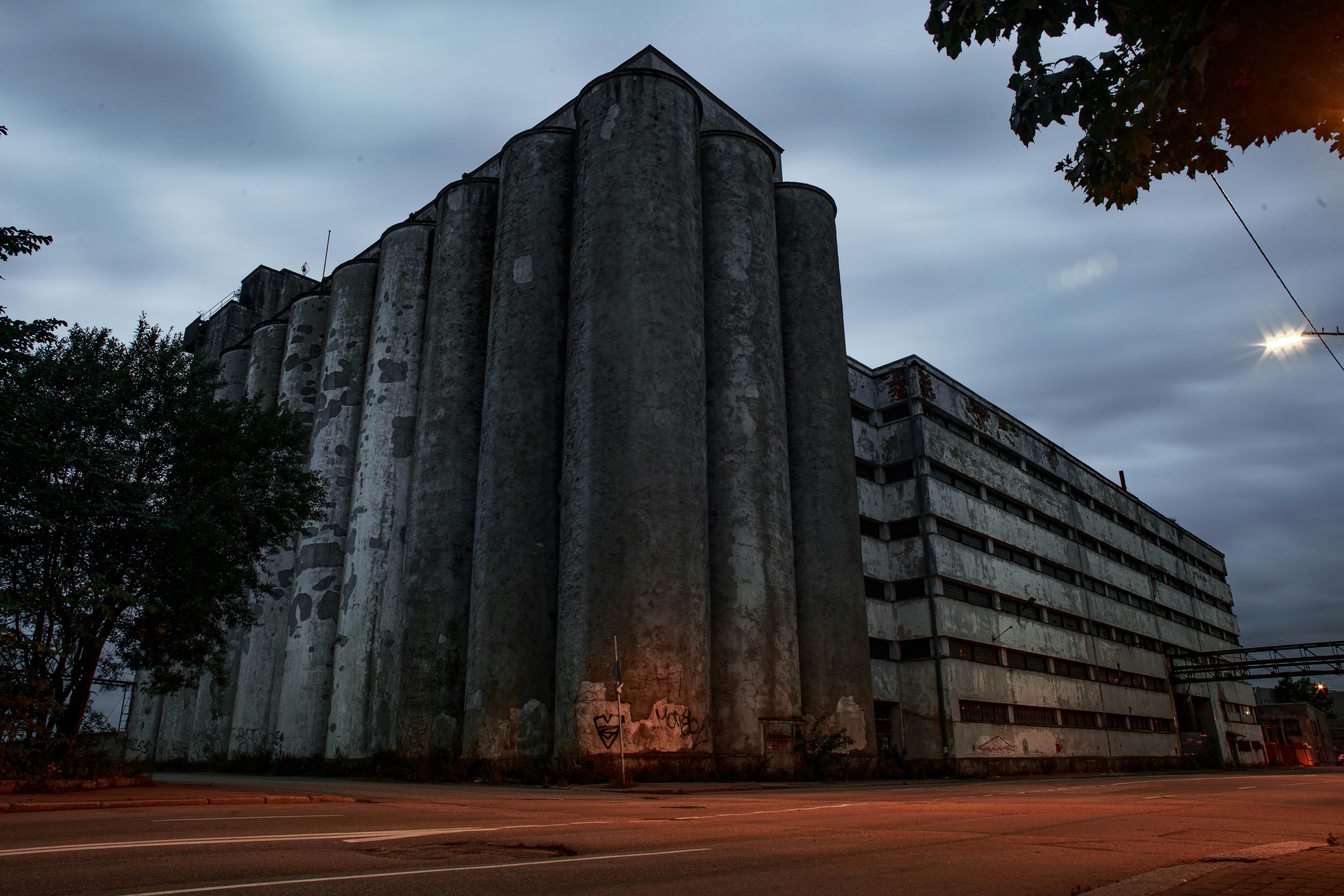 Industrial Giants at Dusk: The Weathered Silos Loom Over a Quiet Street