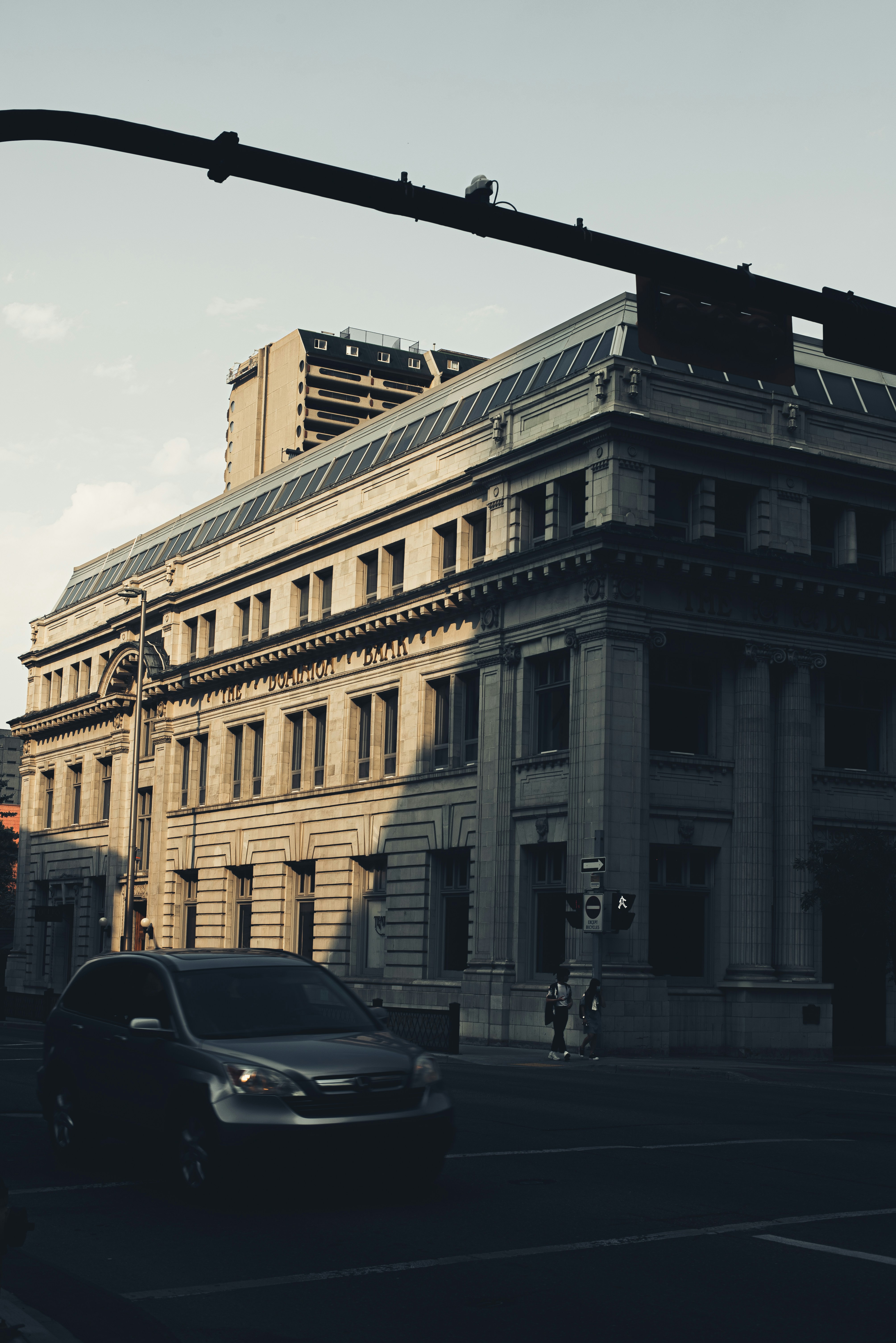 Historic building with intricate stonework and modern urban backdrop, captured during golden hour. Traffic signals and vehicles add to the lively street scene.