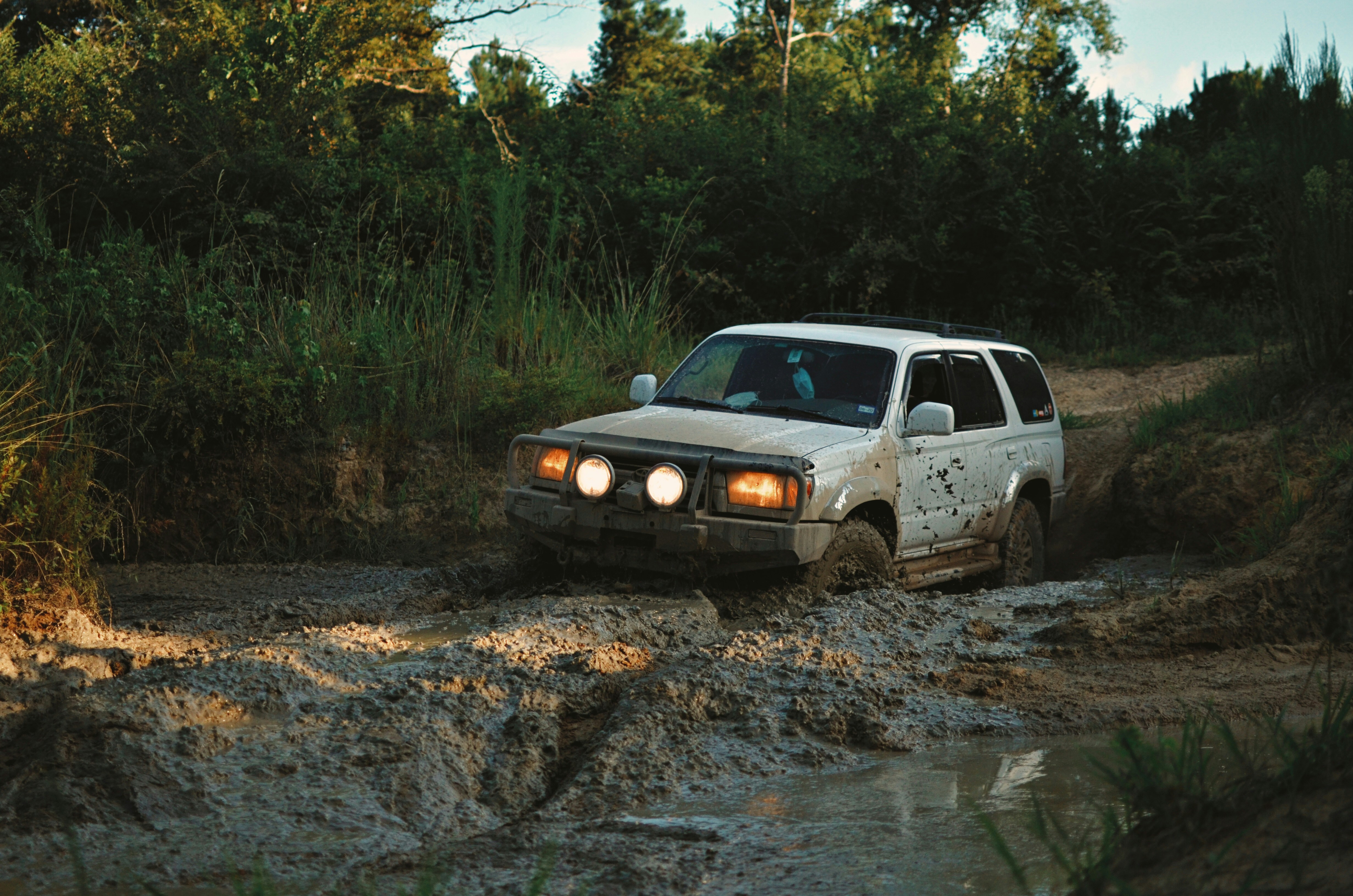 Off-road vehicle navigating a muddy path surrounded by lush greenery. The scene captures the thrill of adventure in challenging terrain.