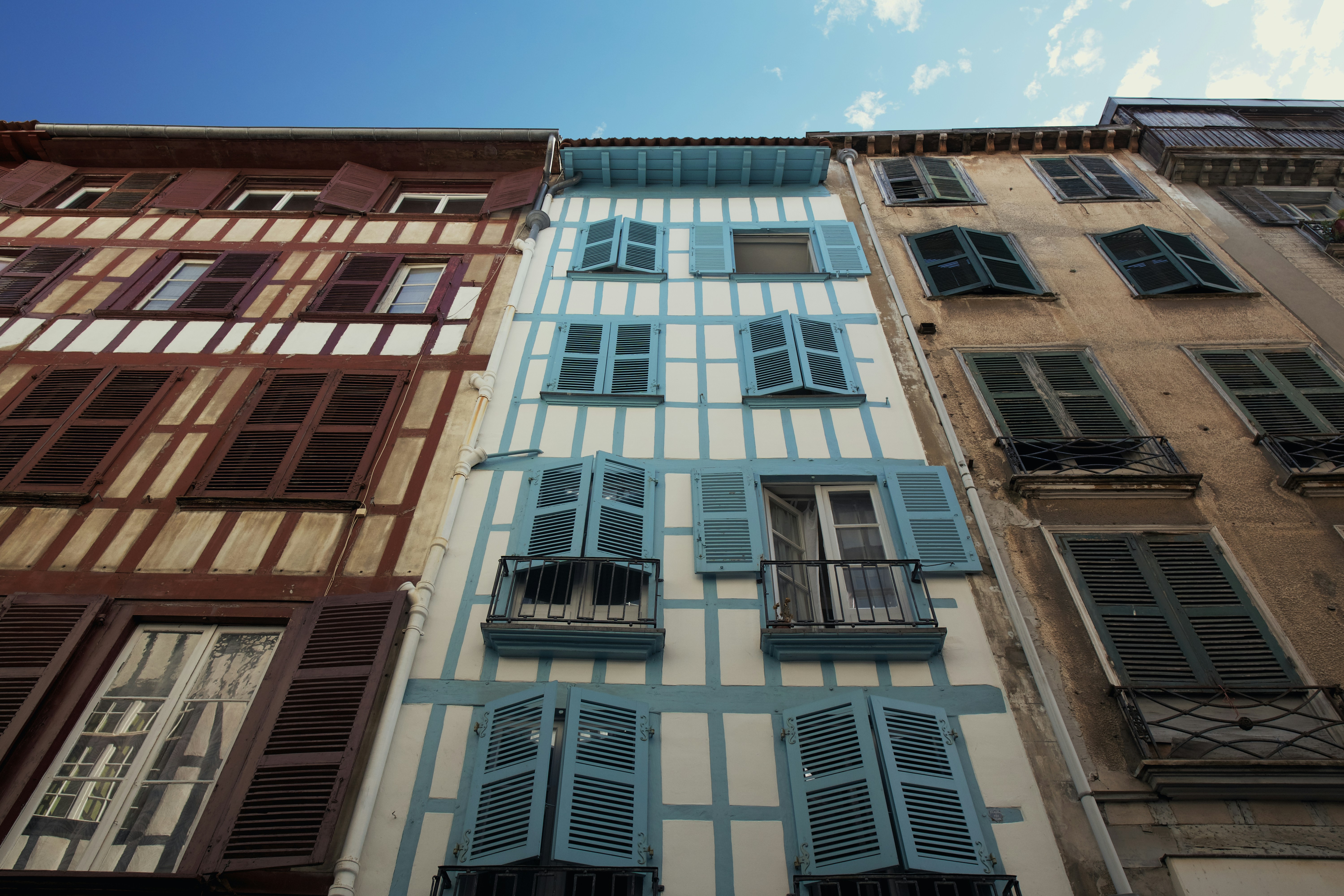 Colorful facades of historic buildings with vibrant shutters under a clear blue sky.