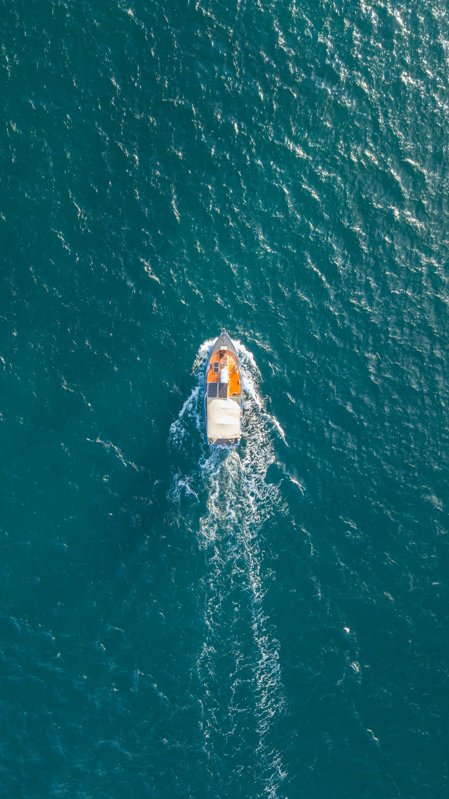 Fishing boat on open water | white and orange boat on blue sea during daytime