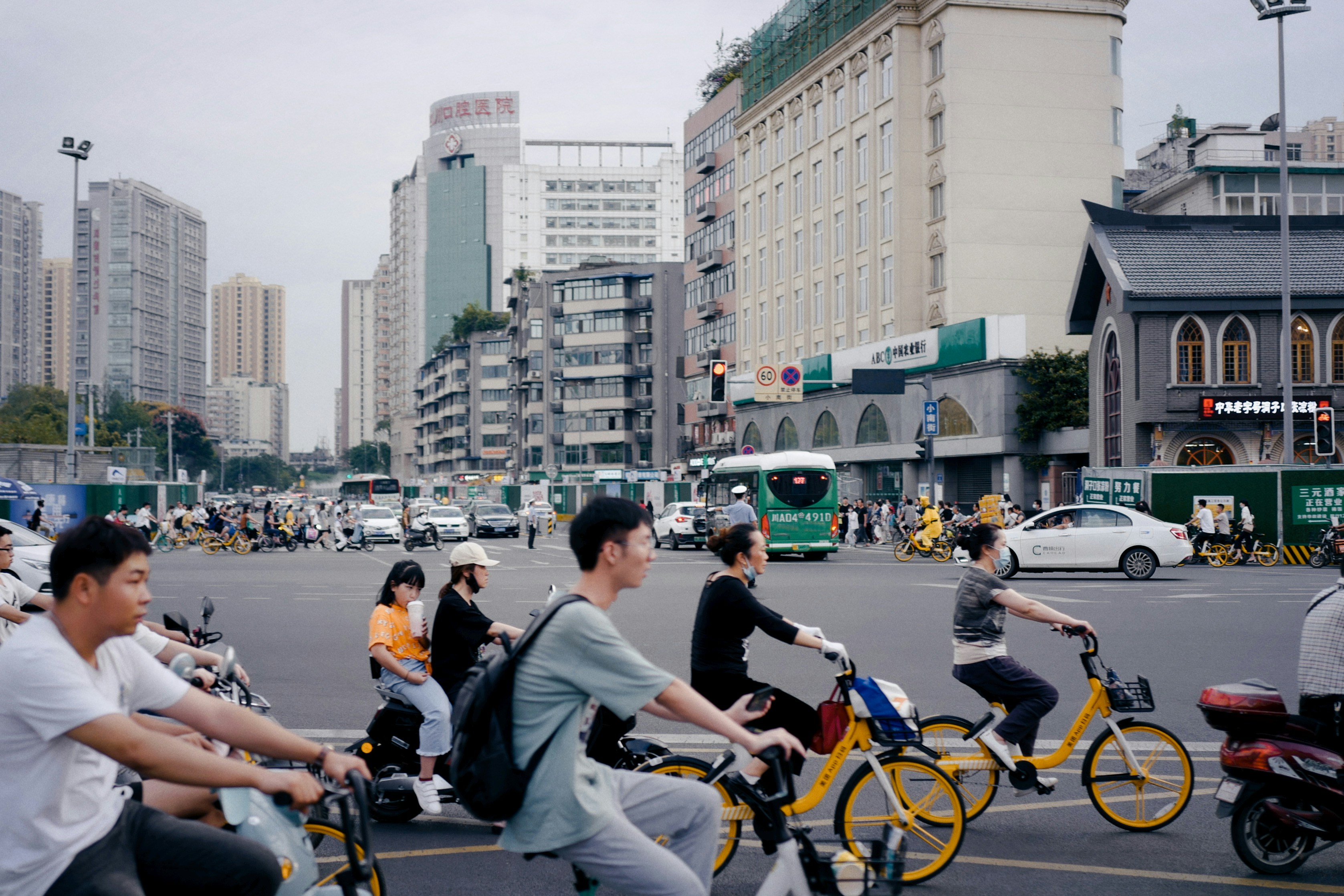 Busy urban intersection filled with cyclists and cars, showcasing the vibrant flow of city transportation.