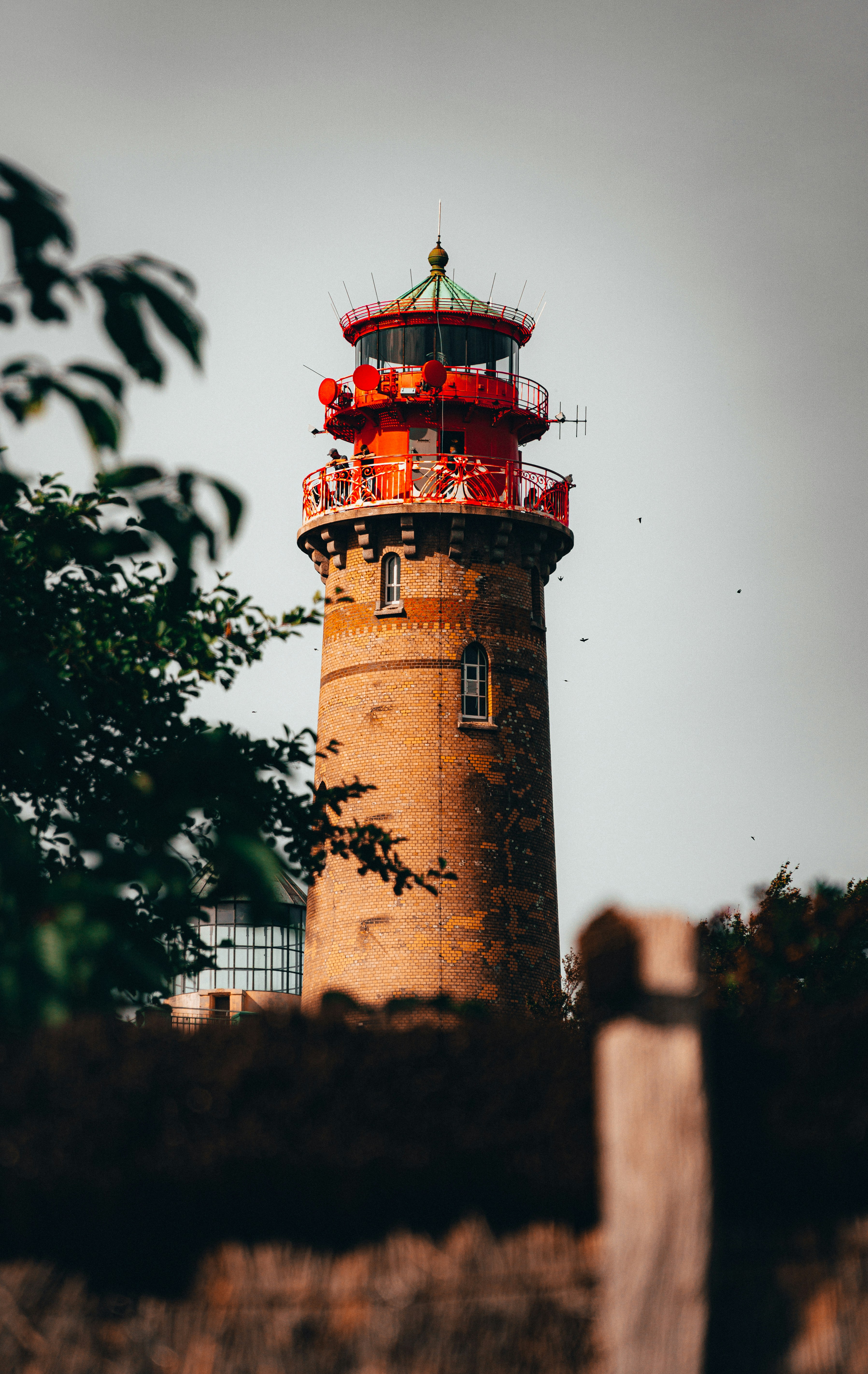 Crimson Lantern on a Brick Lighthouse Against a Quiet Sky