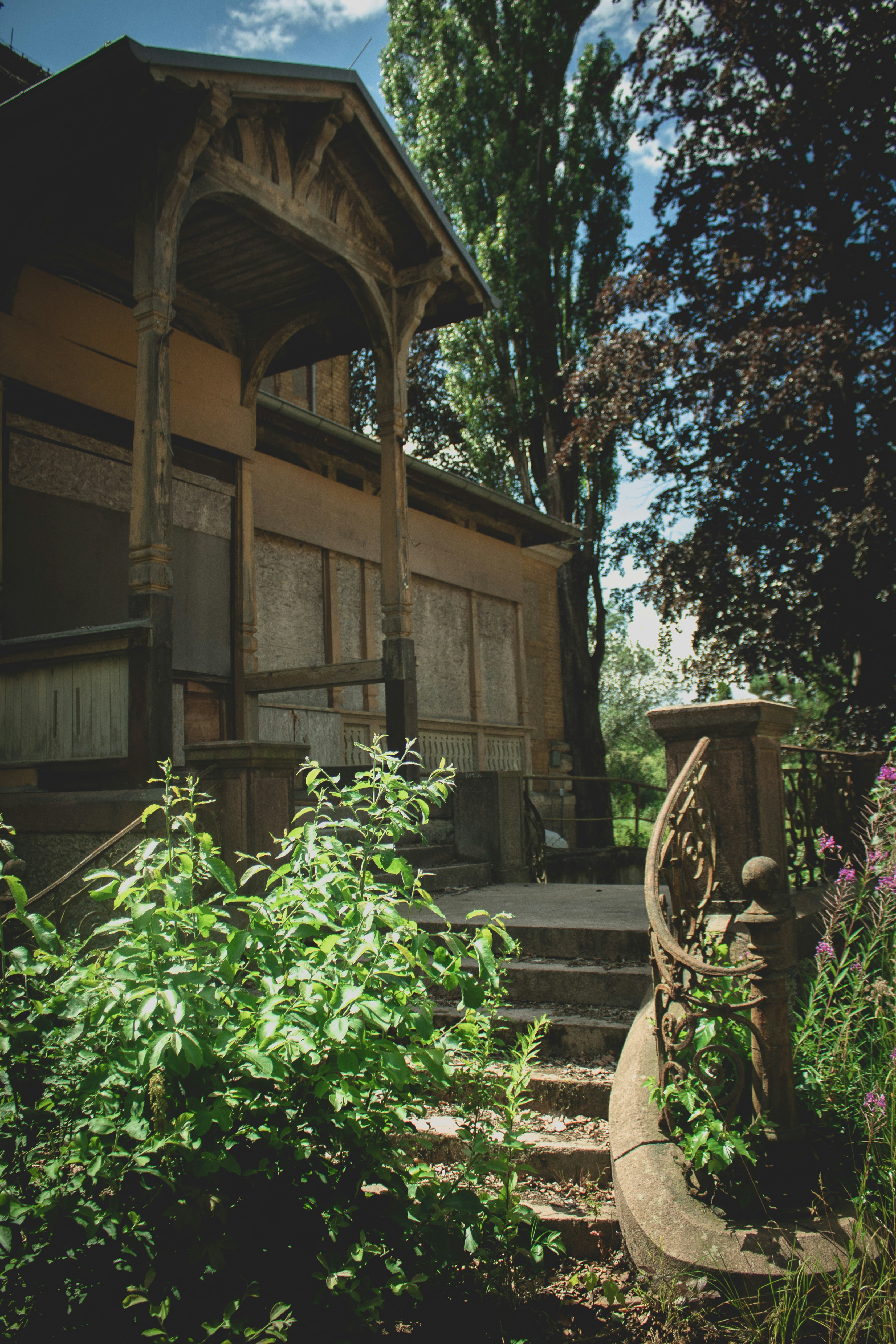 Abandoned building with intricate wooden architecture and overgrown greenery, showcasing nature reclaiming its space.