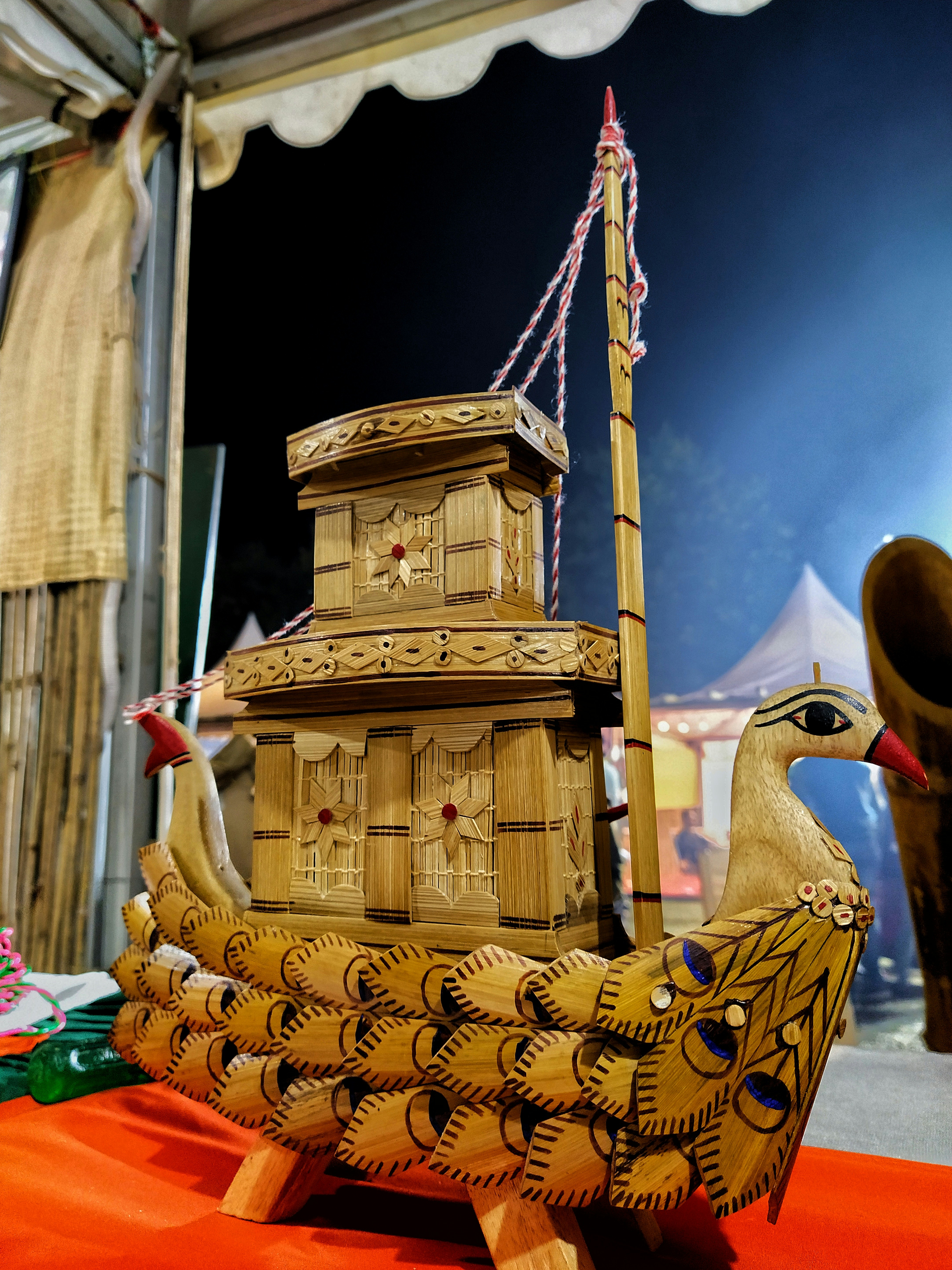 Night Parade: A carved wooden shrine perched on ornate peacock pedestals