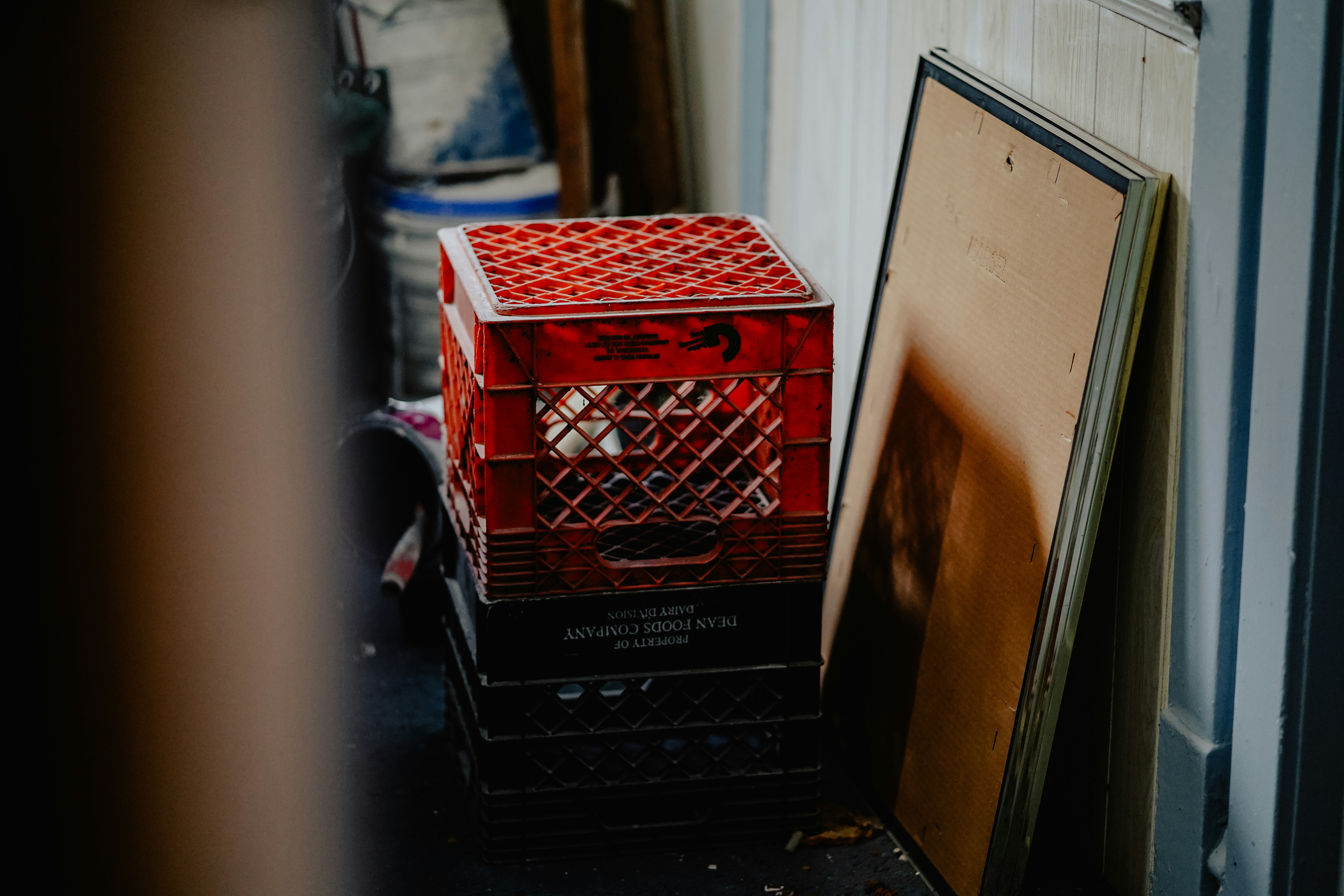 Stacked red crates beside a leaning wooden panel, showcasing an urban environment's overlooked details.