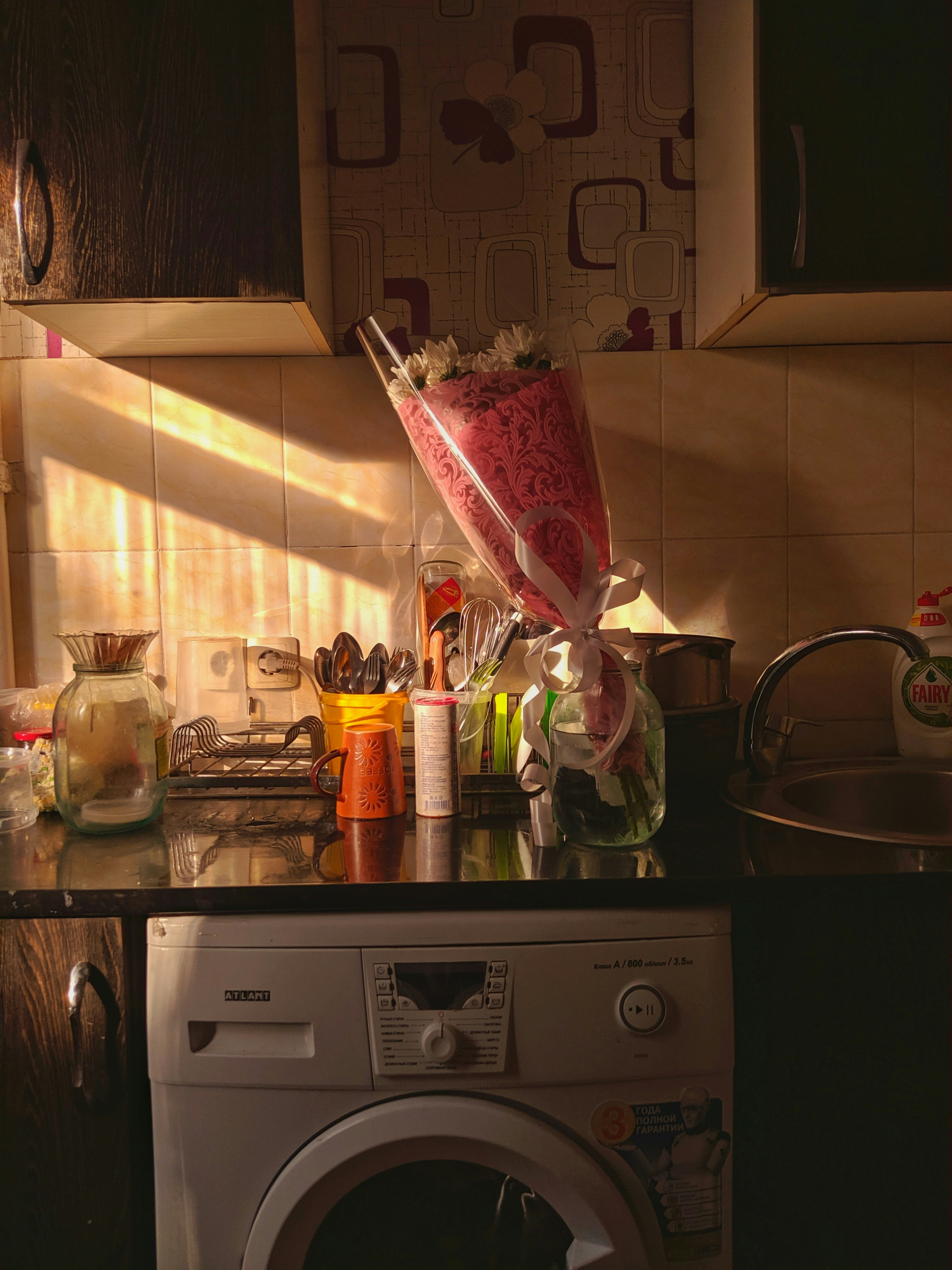 Amber Kitchen Still Life: Pink Bouquet on a Cluttered Counter