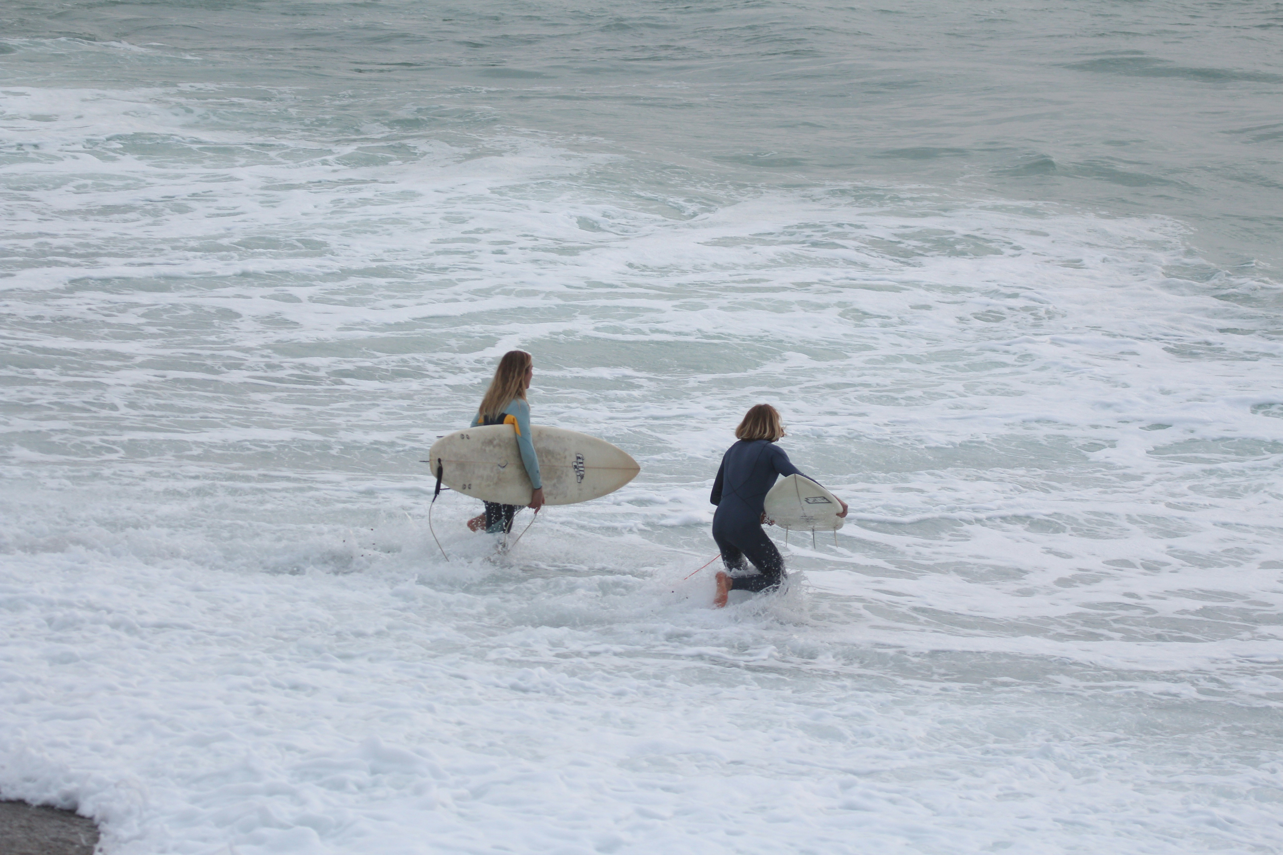 Waiting for the Break: Two Surfers Edge Into the Foamy Sea