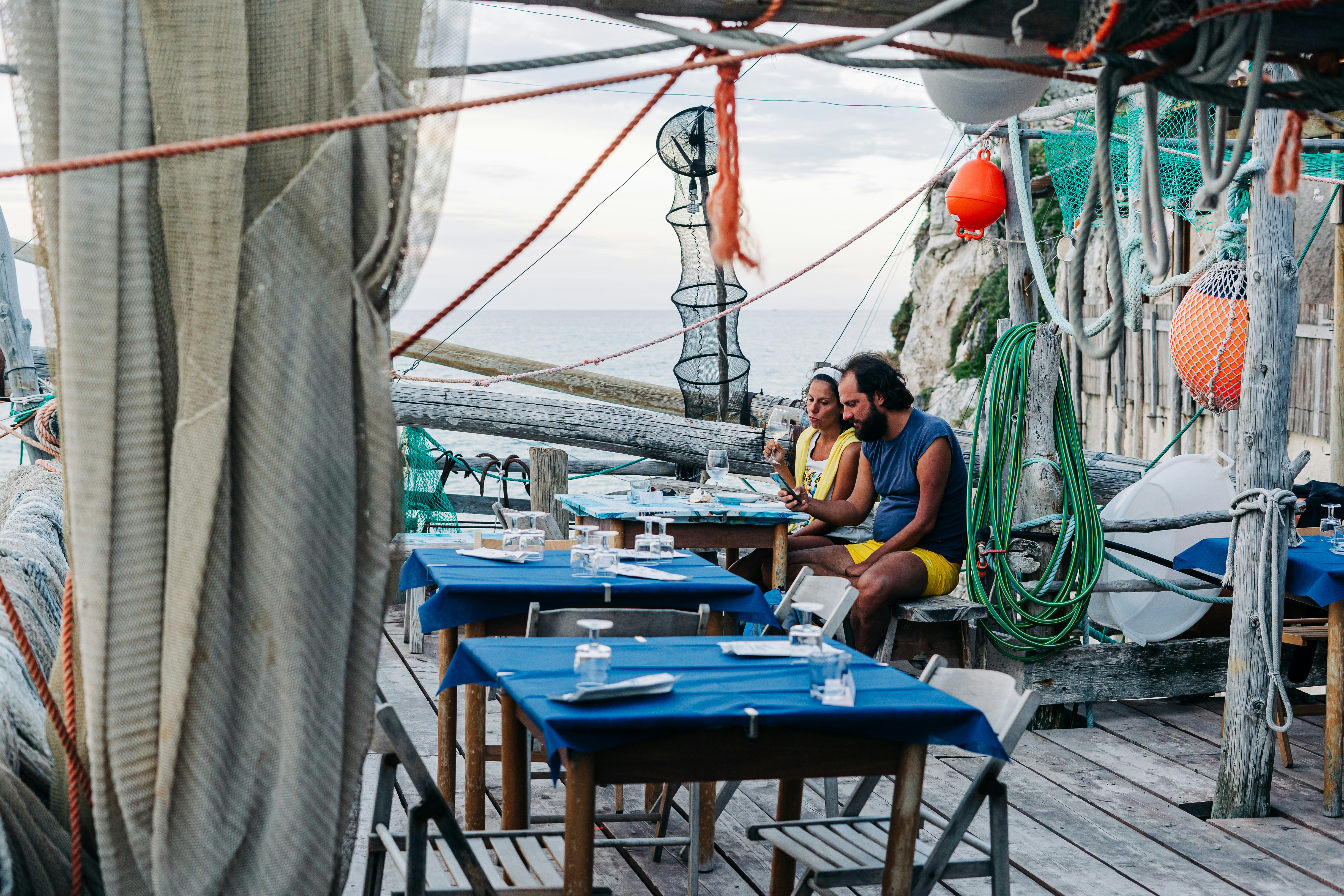 A couple enjoys dinner in a characteristic trabucco or fishing platform on the northern coast of Puglia, Italy