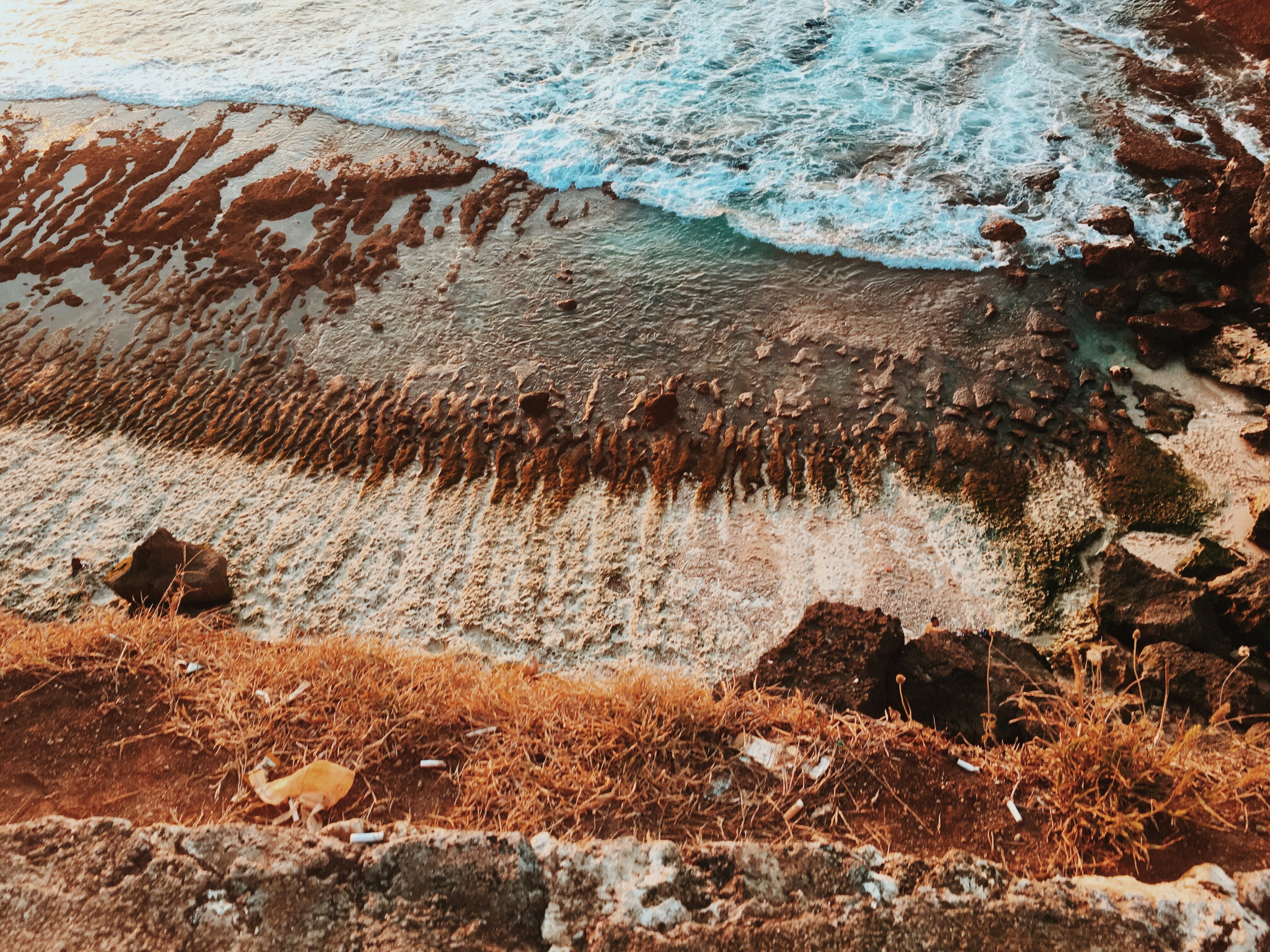 brown rocky shore with water waves during daytime