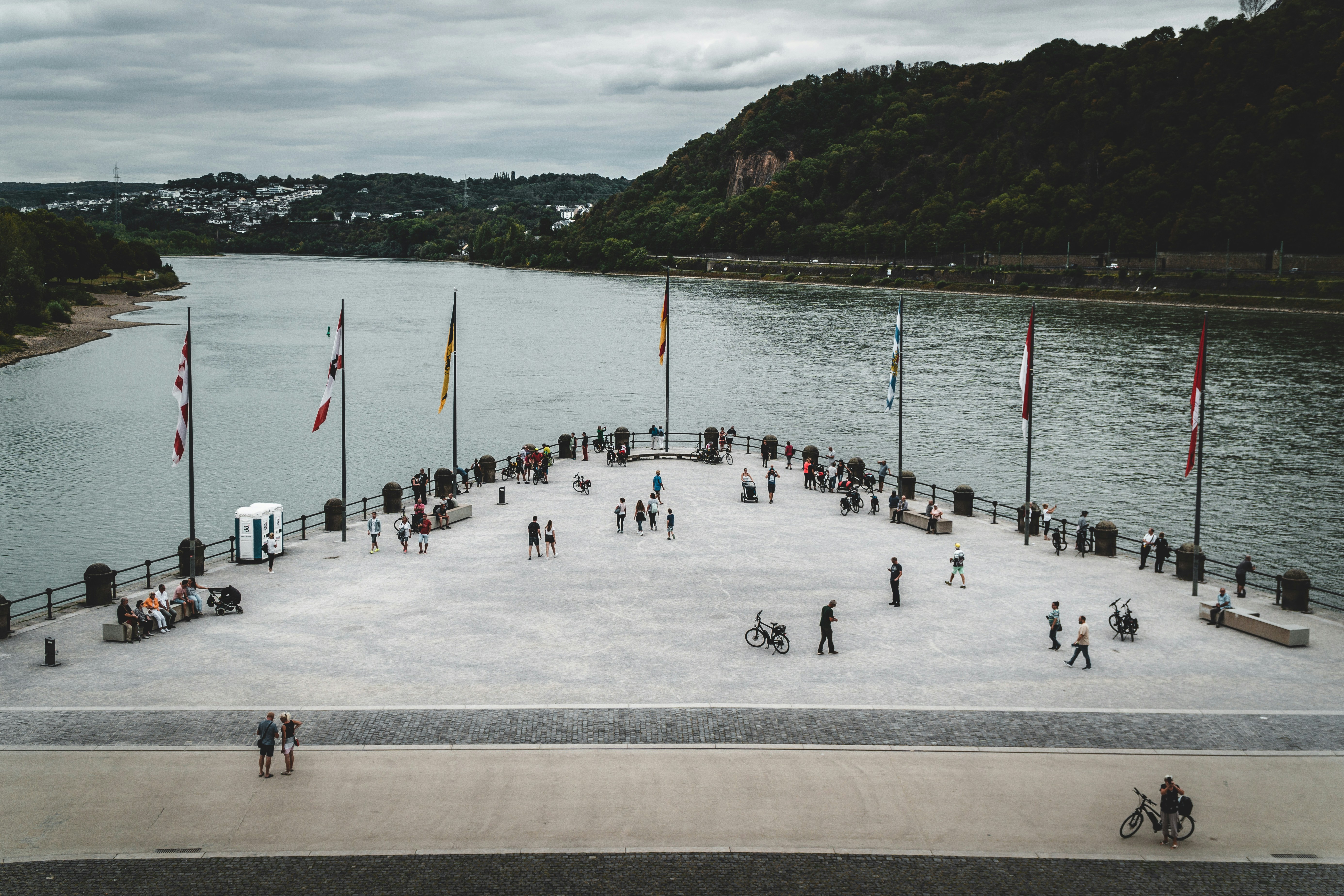 Flag-Lined Riverside Plaza: Quiet Pedestrian Pulse by the Water