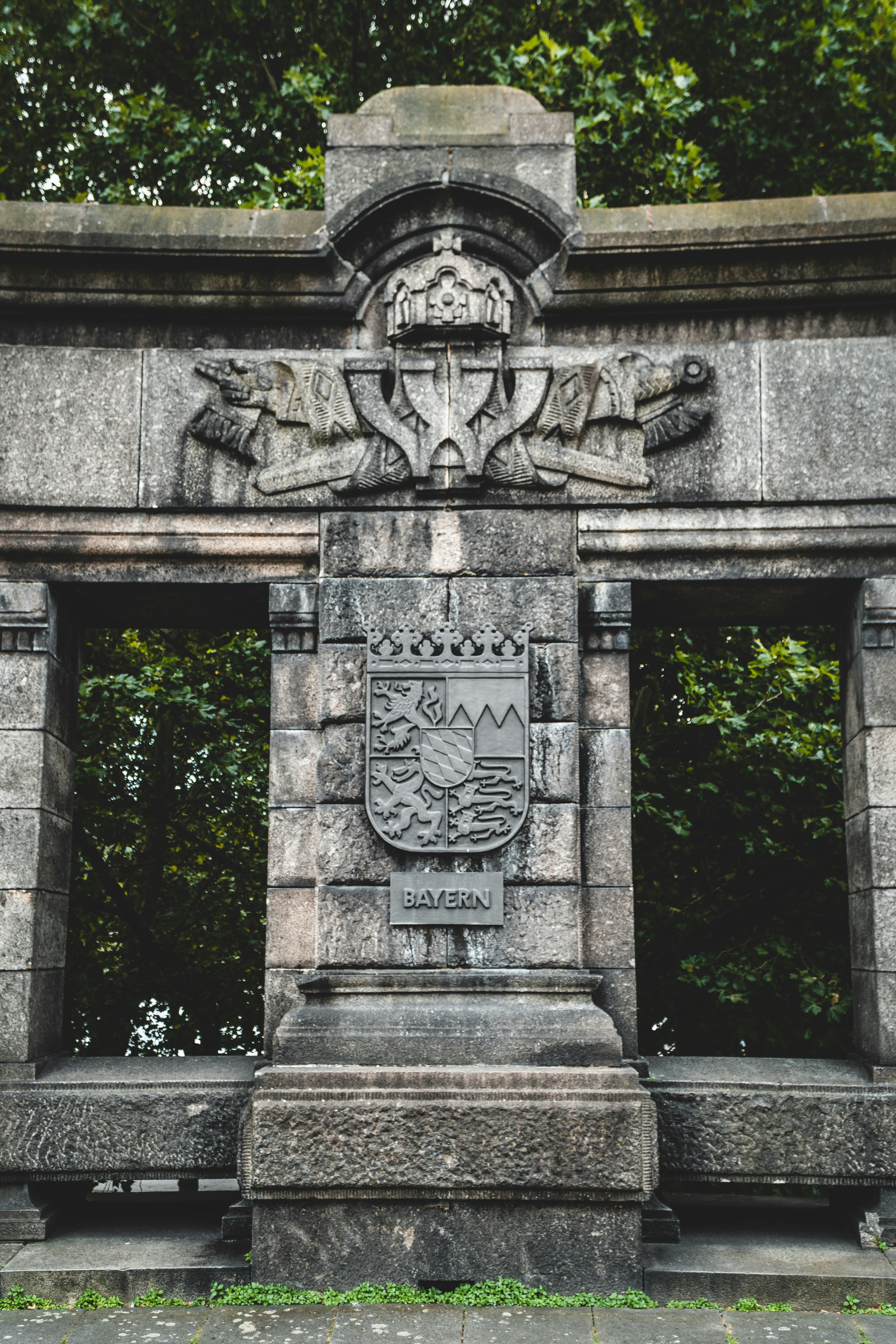 Intricate stone relief featuring a coat of arms and mythical creatures, symbolizing Bayern's heritage and strength.