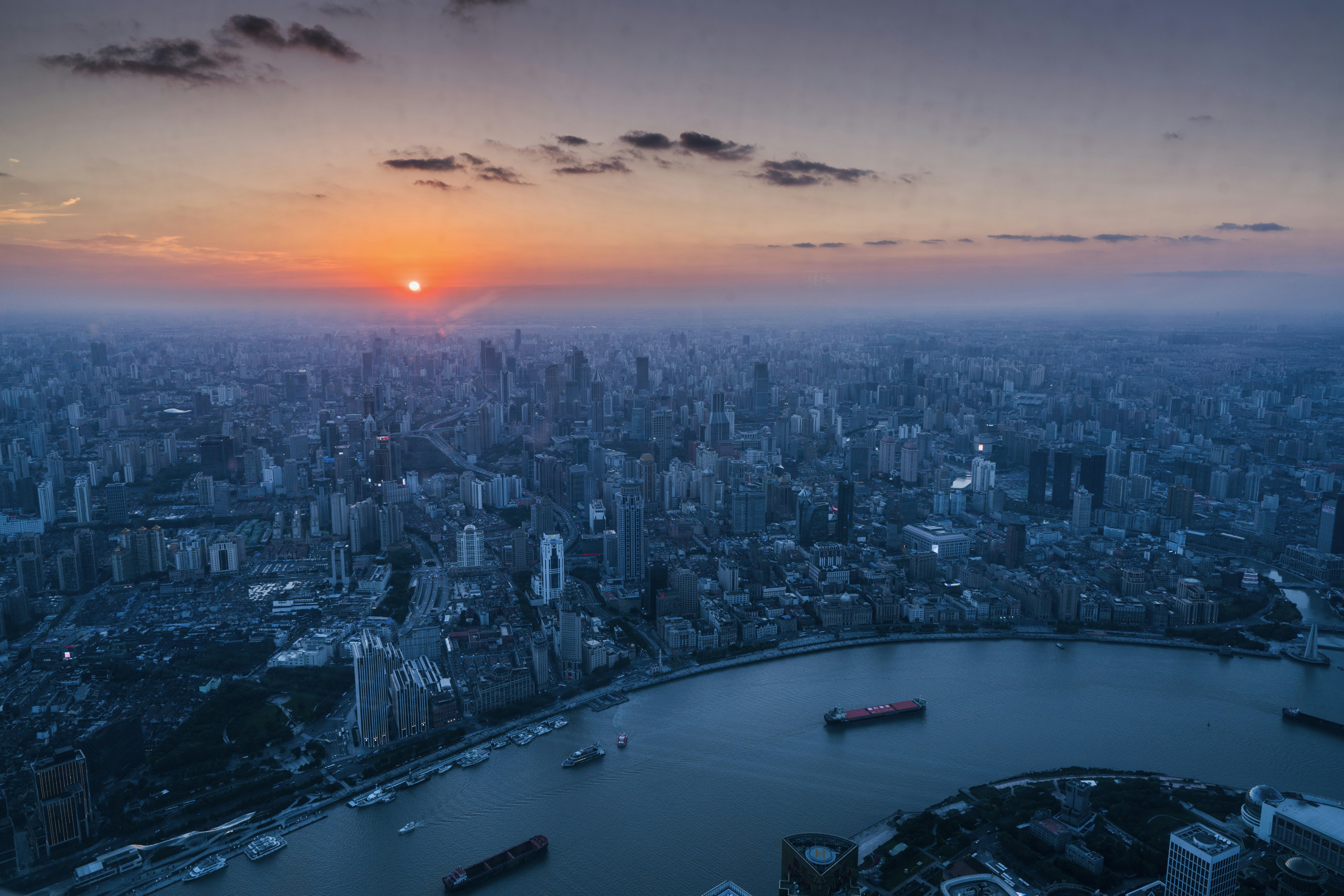 City skyline at sunrise with a river curving through the foreground.