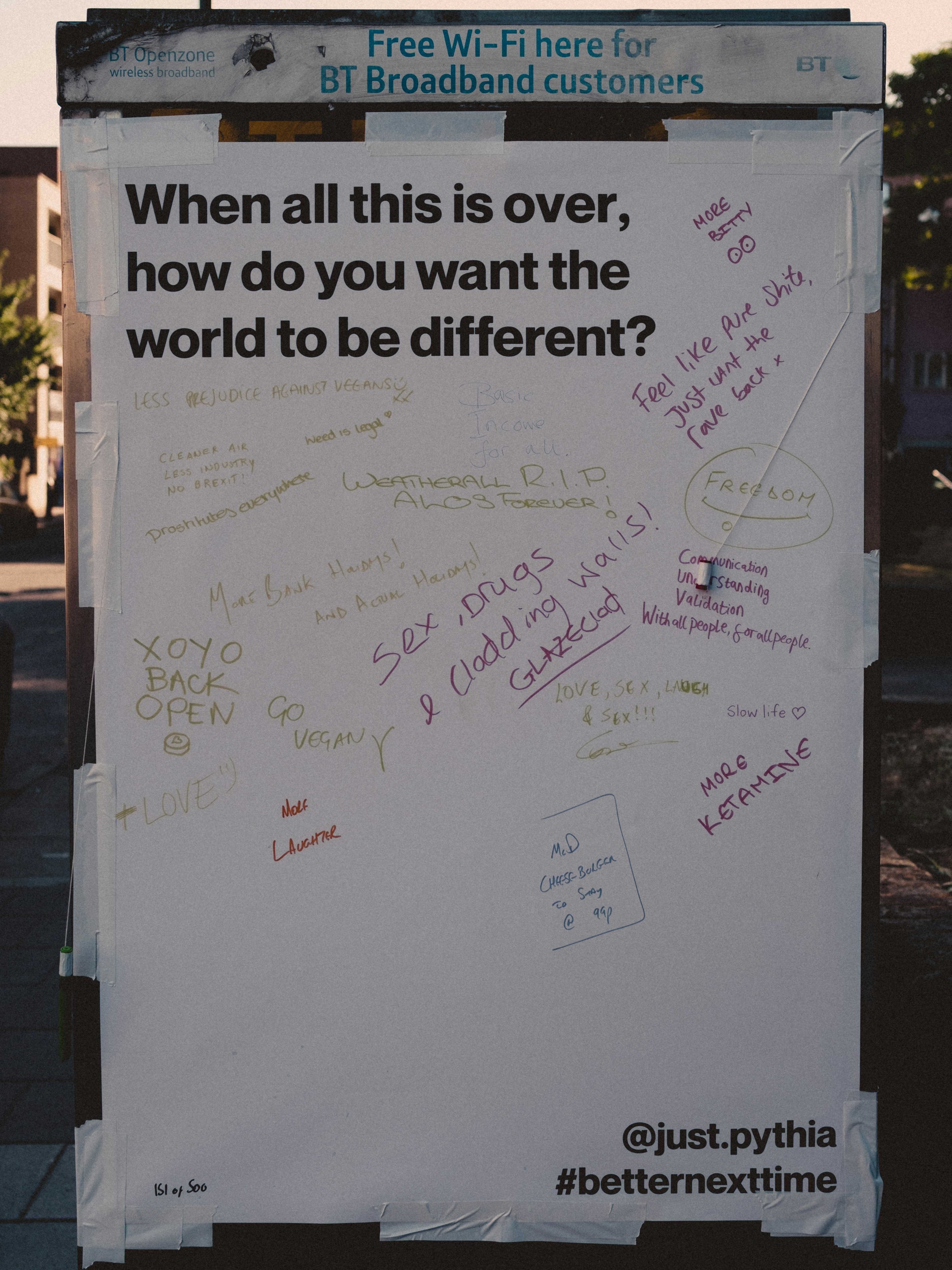Community message board filled with handwritten thoughts and suggestions on how to improve the world post-pandemic. Various colorful notes express hopes and desires for change.