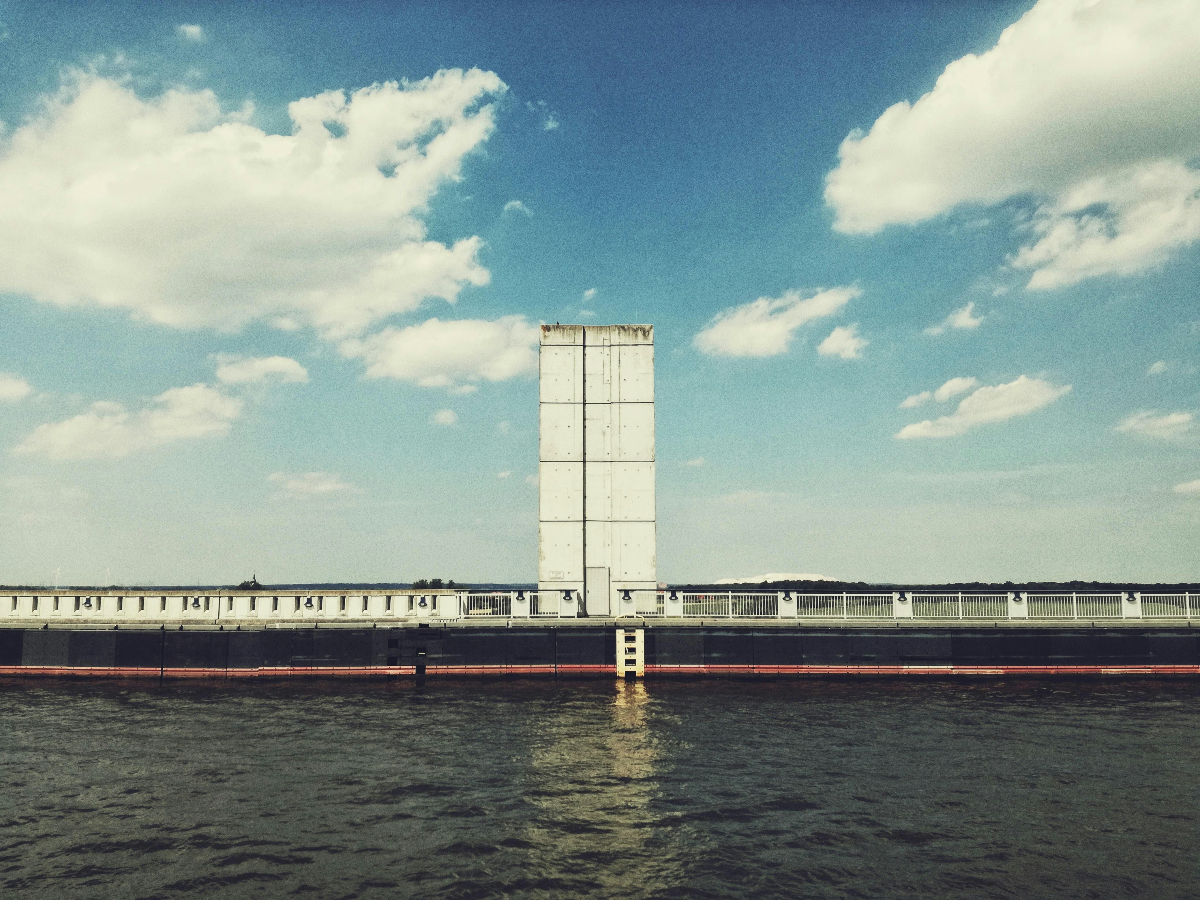Bridge spanning across a wide river under a sky with scattered clouds.
