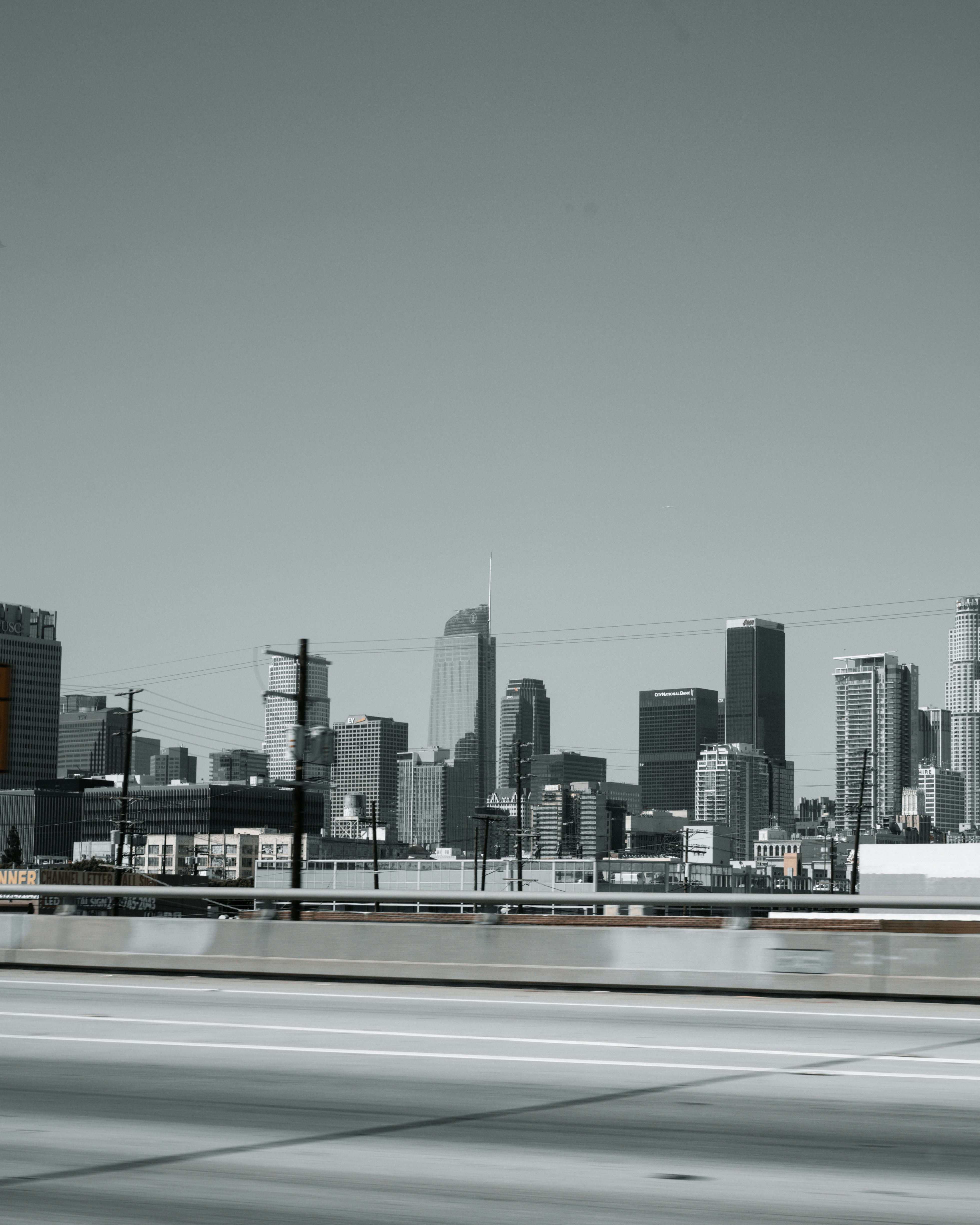 A monochromatic view of a bustling city skyline, showcasing a mix of modern architecture and urban elements. The image captures the essence of city life with a dynamic composition.