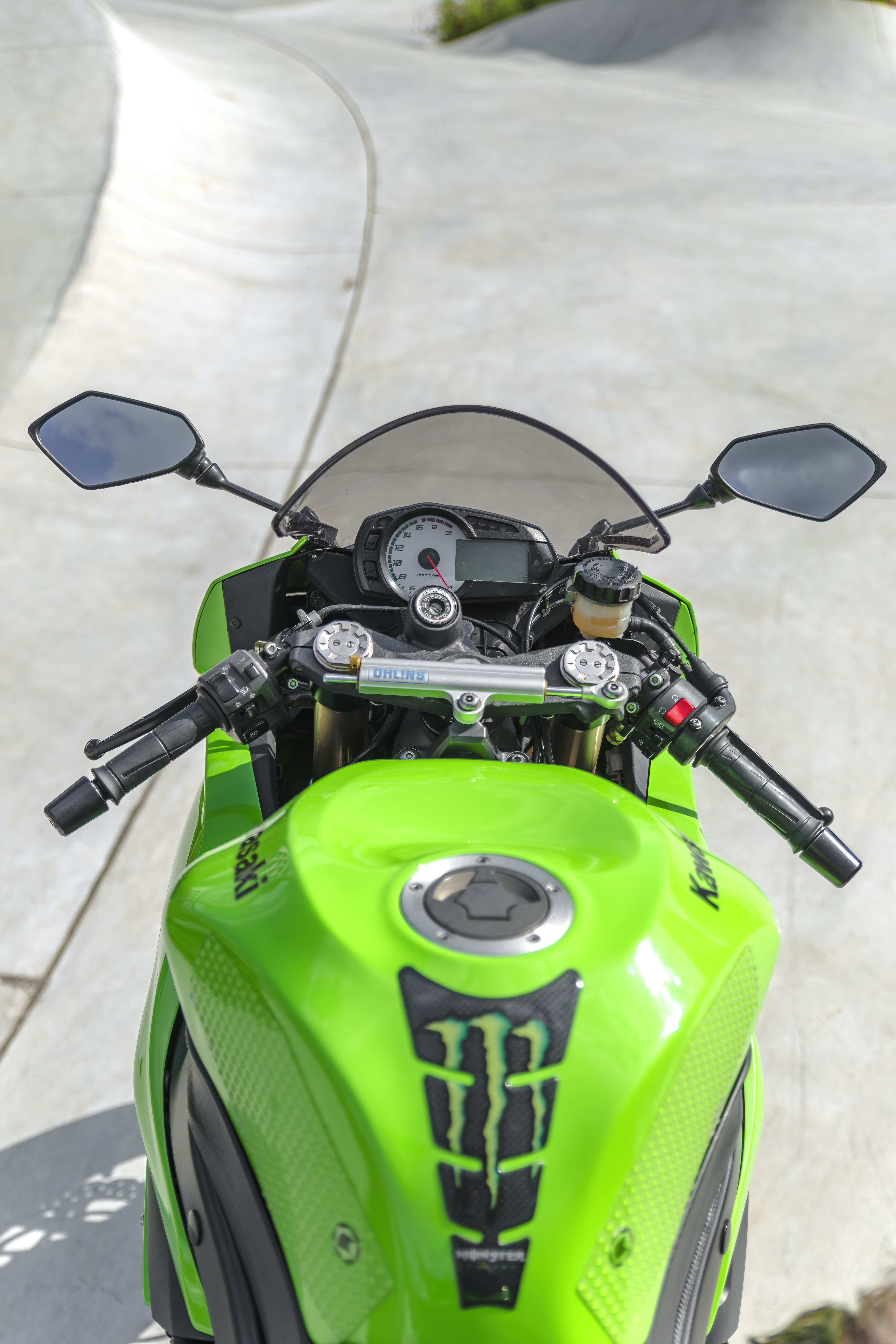 Close-up view of a green Kawasaki motorcycle's handlebars and dashboard, showcasing its sleek design and intricate details.
