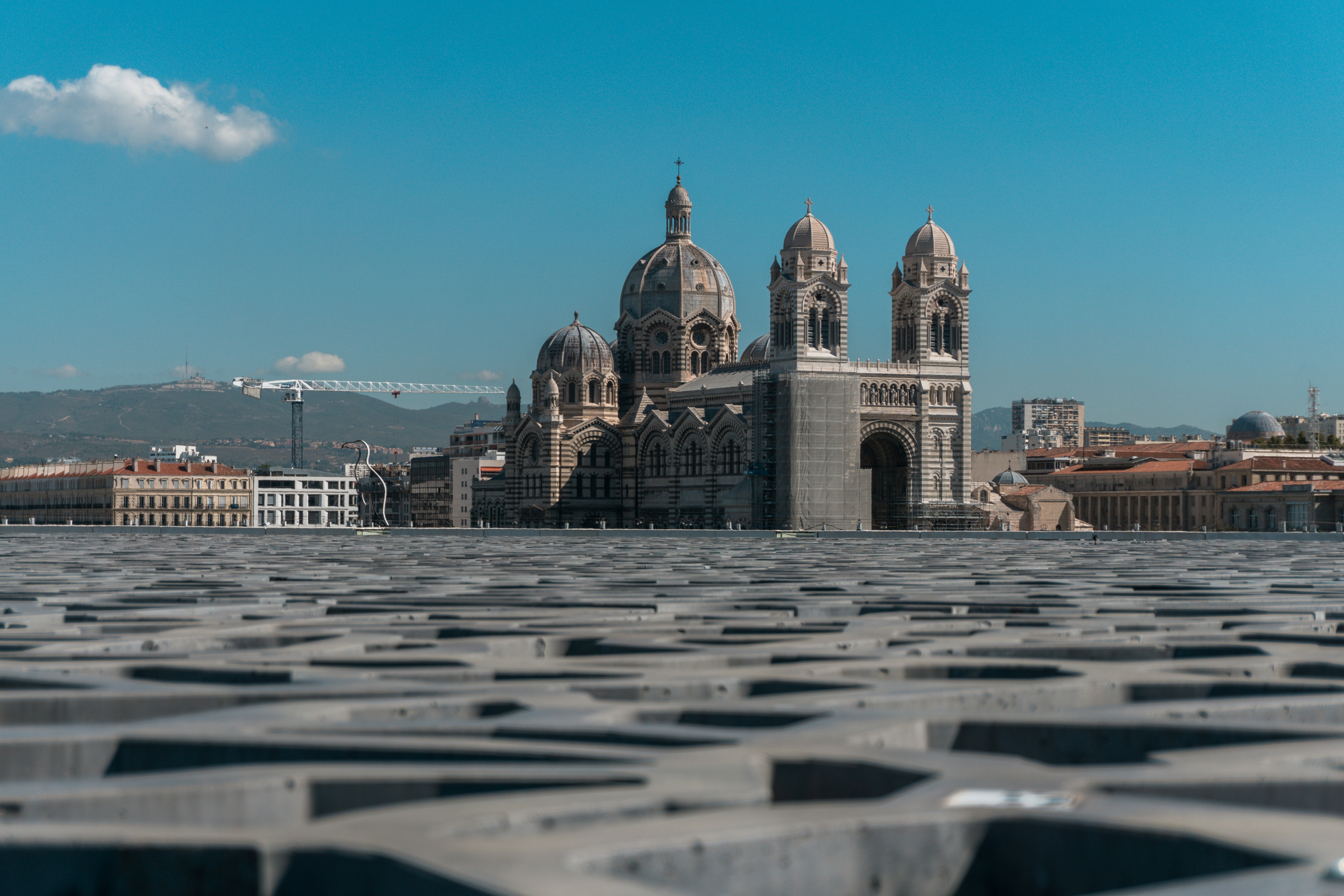 Historic cathedral framed by intricate modern architecture against a bright blue sky.