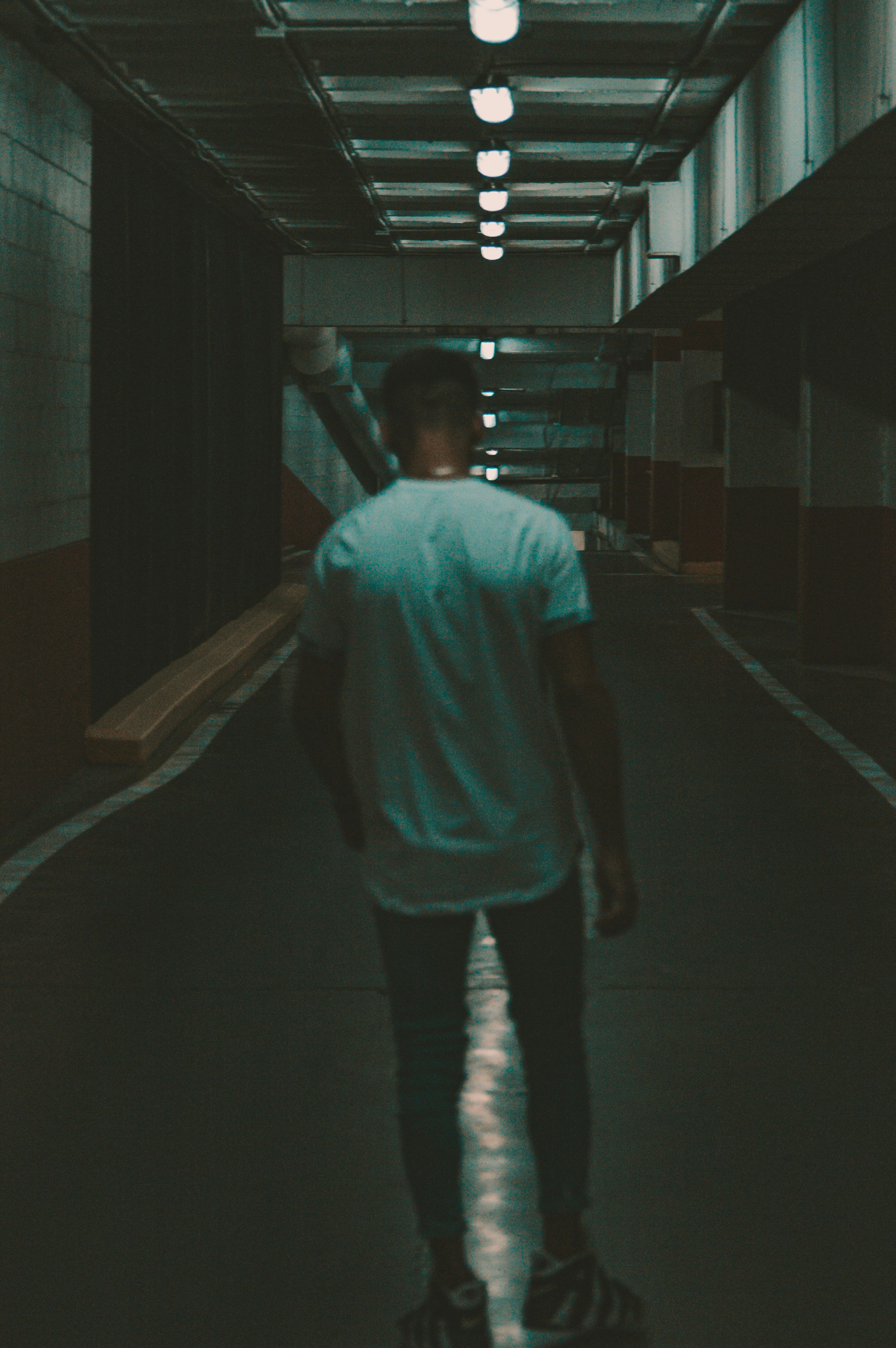 A figure walks through a dimly lit underground corridor, emphasizing a sense of isolation and contemplation.