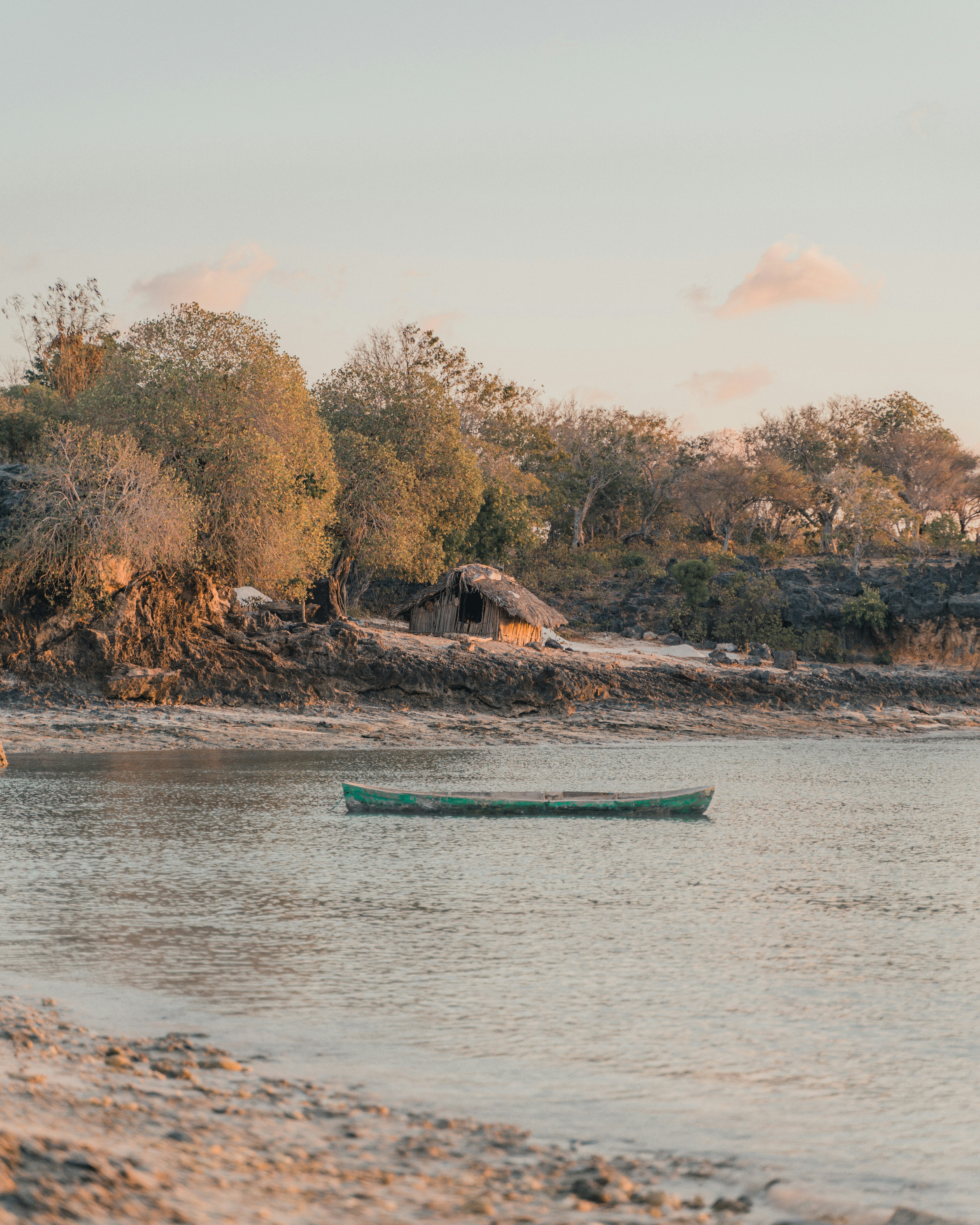 Green Rowboat on a Quiet Riverbank Under Golden Hour Light