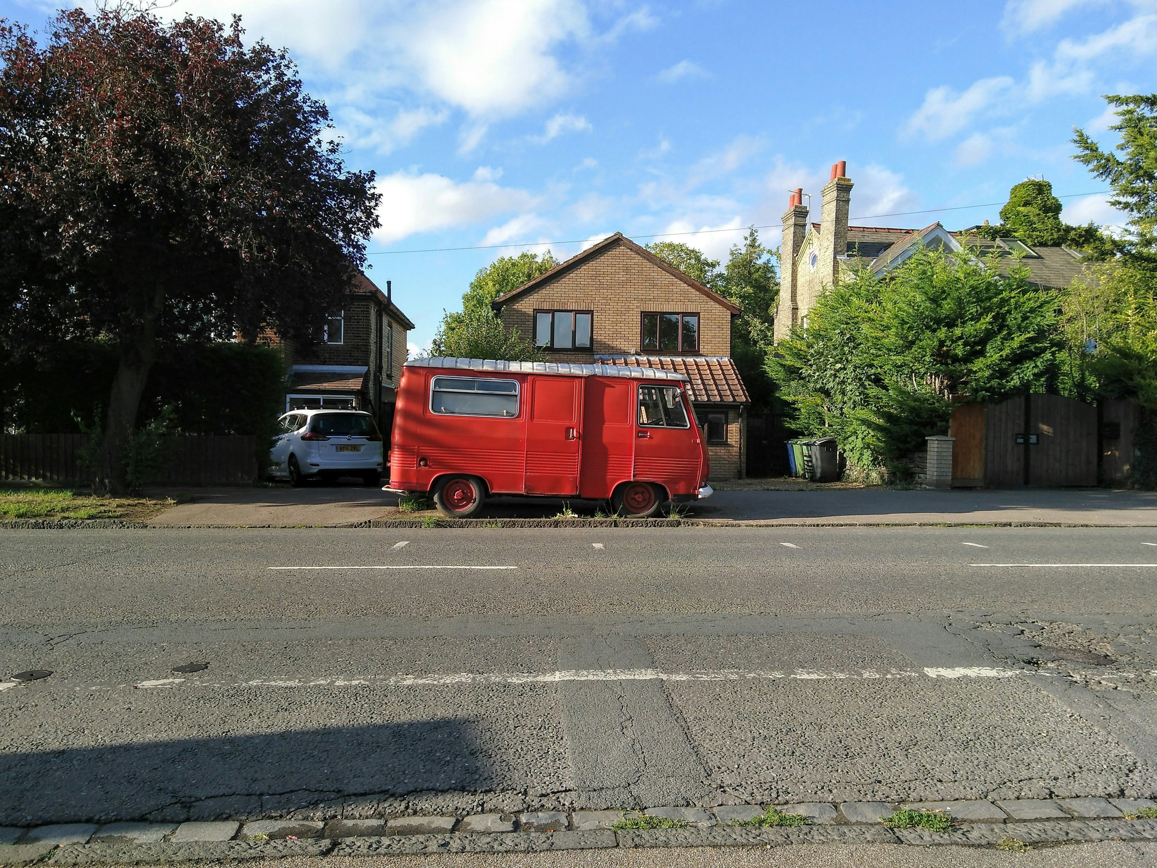 red van parked beside green tree during daytime