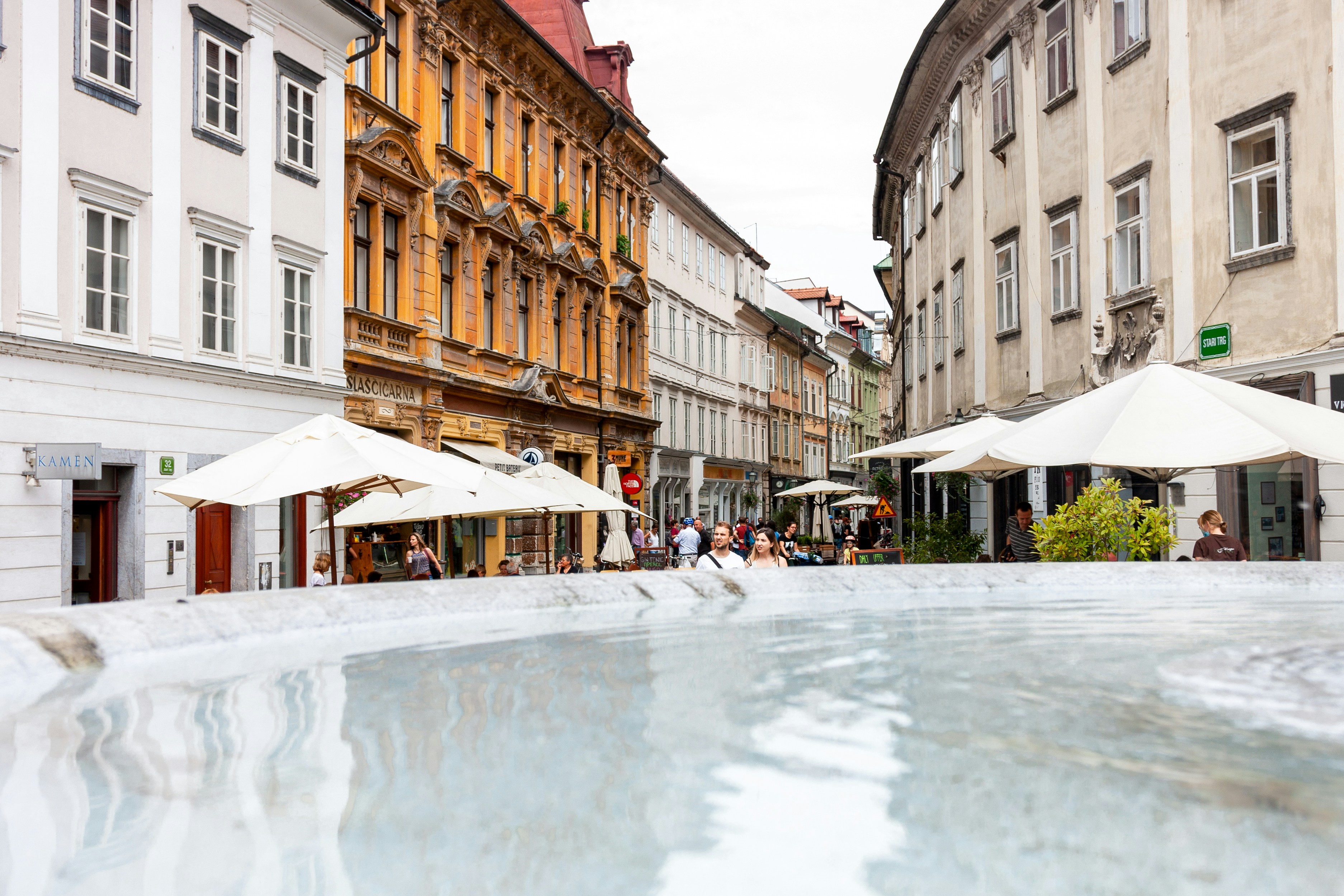 Colorful Riverside Arcade: A European Street Alive with Cafés and Wet Reflections