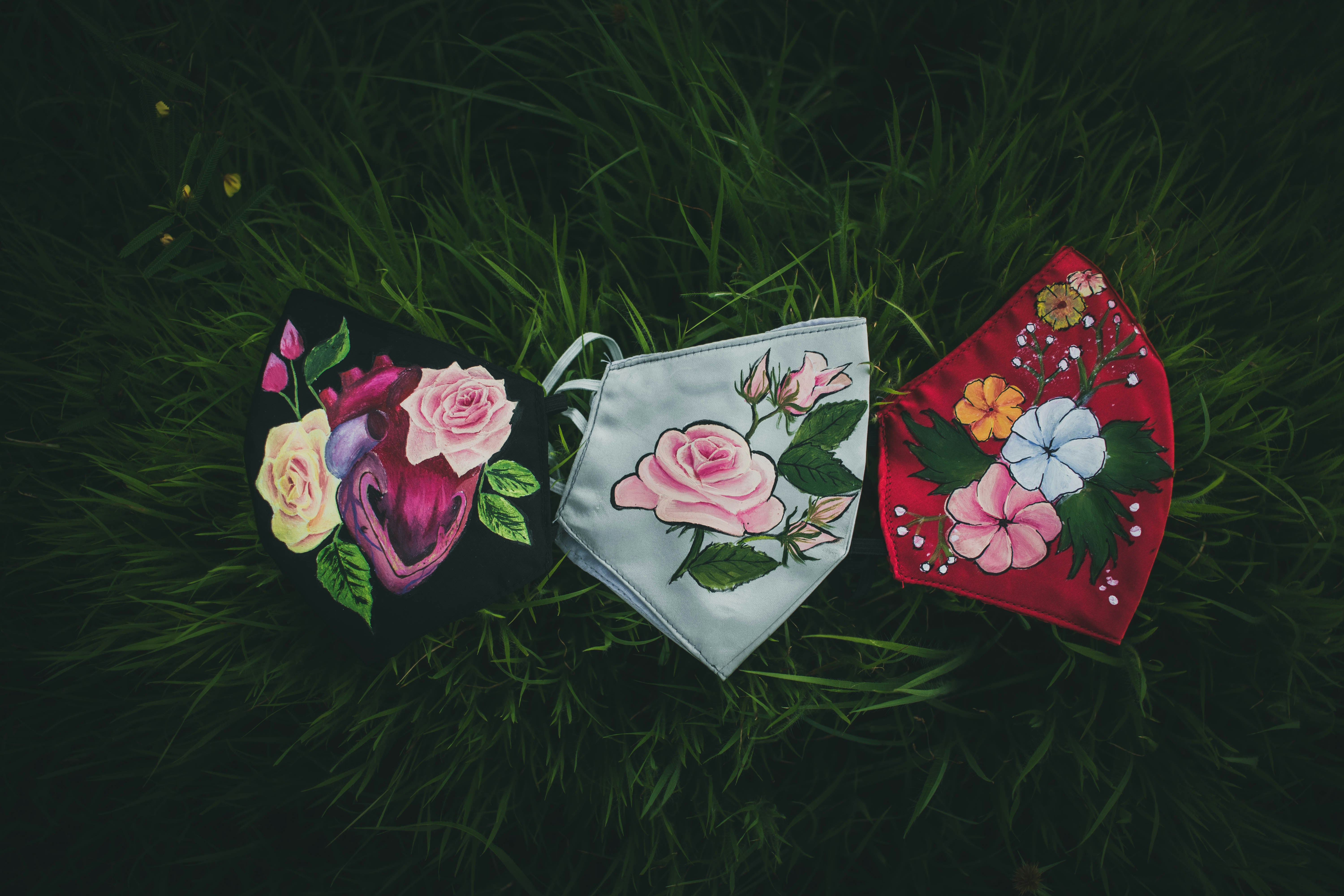 Three Embroidered Floral Hearts Lined Up on Grass at Dusk
