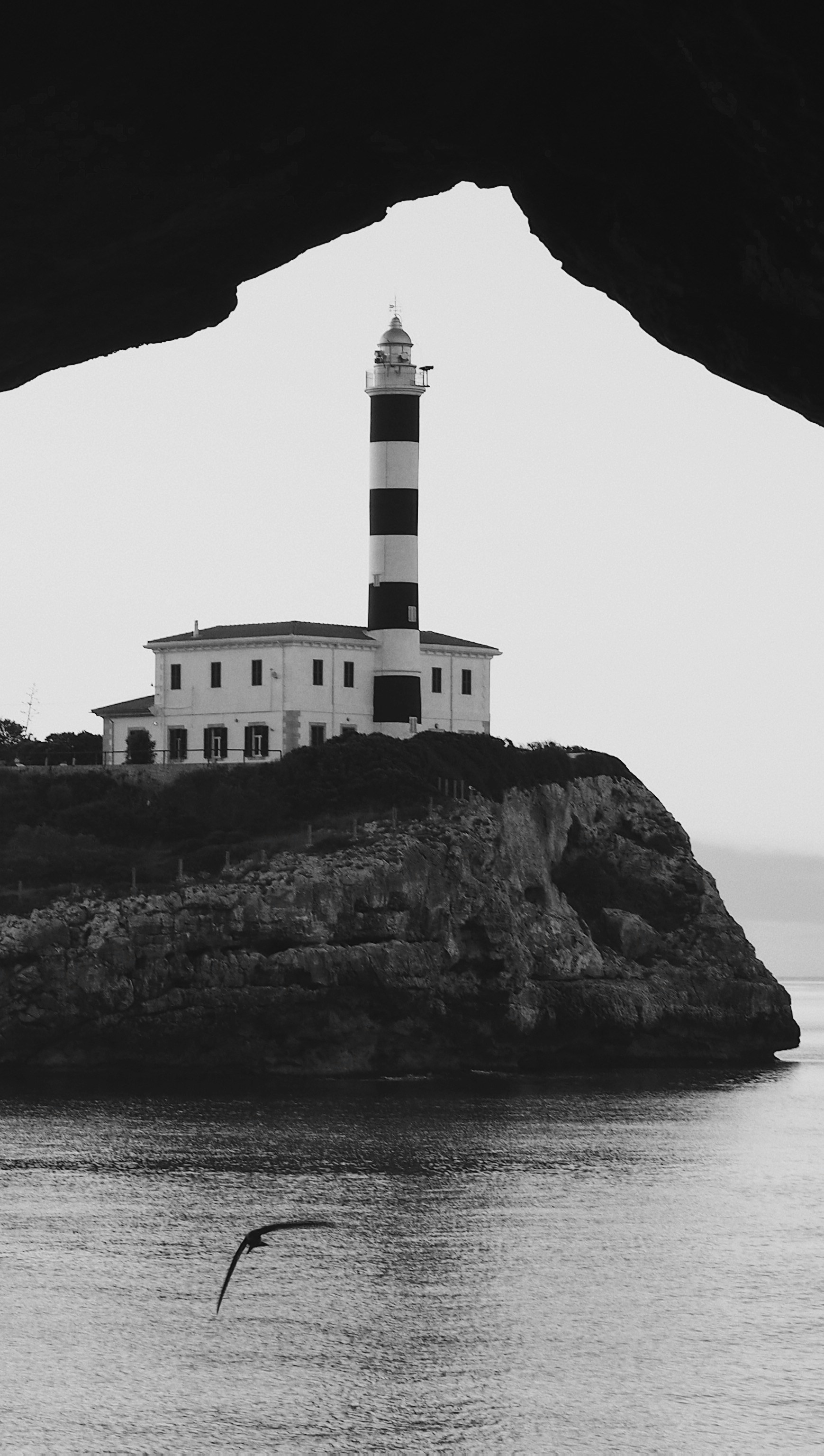 Lighthouse at the Cliff's Edge, Framed by a Cavernous Arch