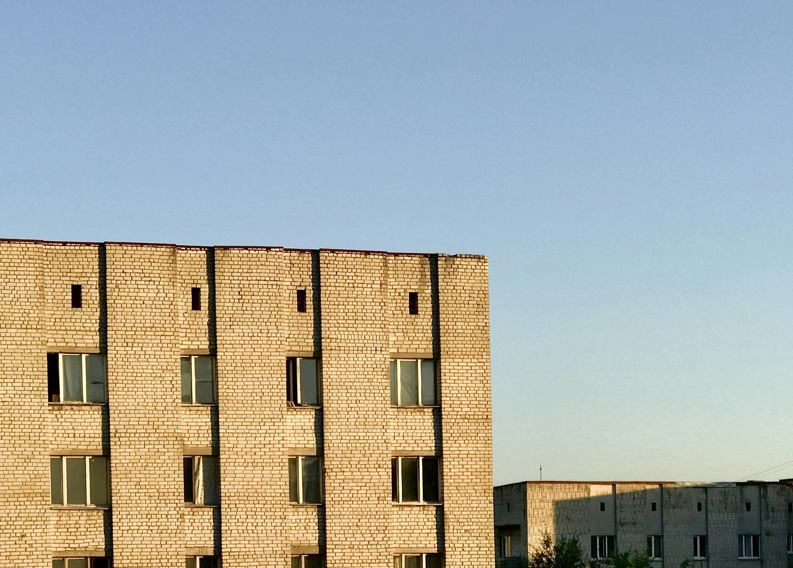 Textured brick building facade under a clear sky, showcasing architectural lines and window placements.