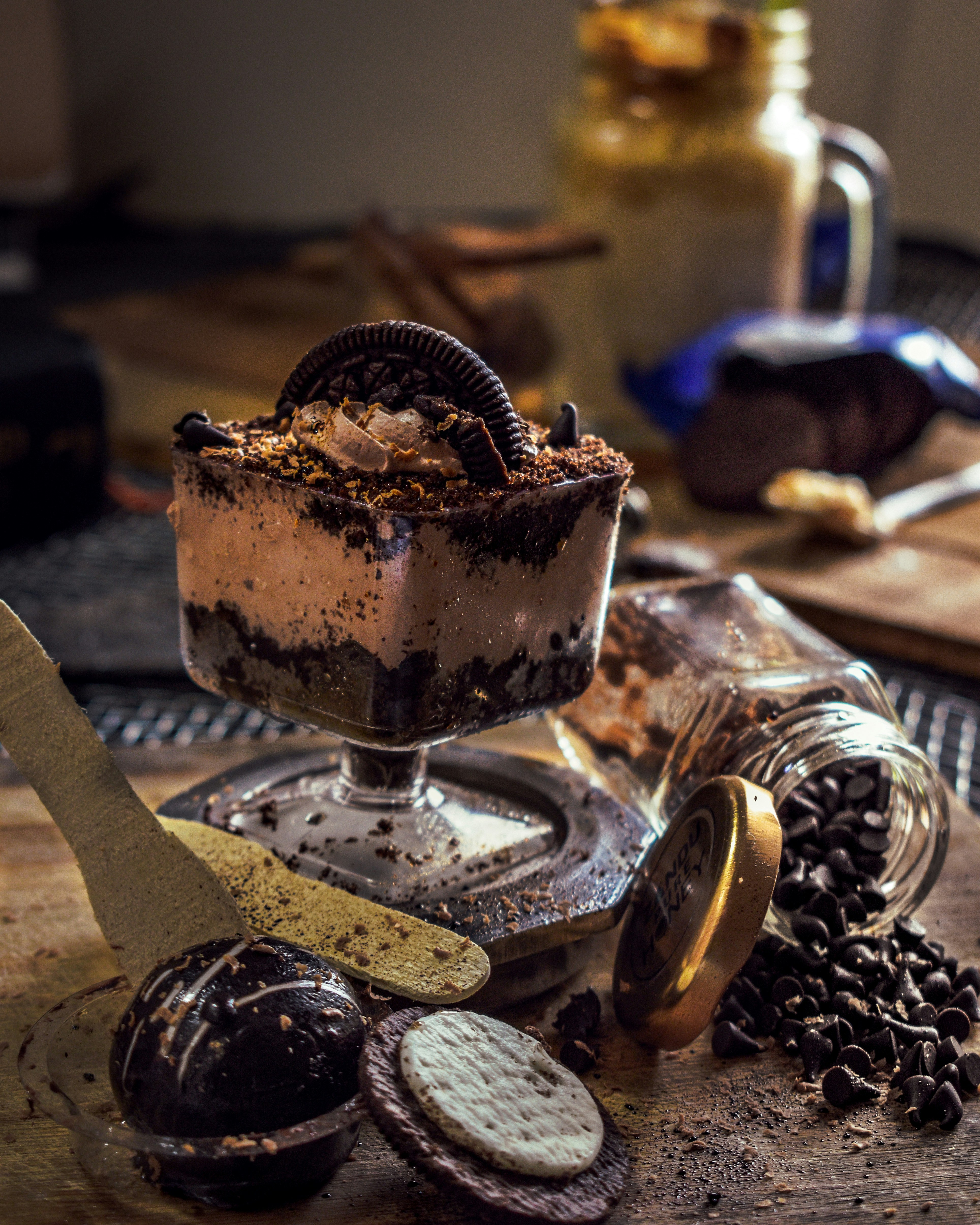 A rich dessert layered with chocolate and cream, topped with crushed cookies, accompanied by chocolate truffles and scattered chocolate chips.