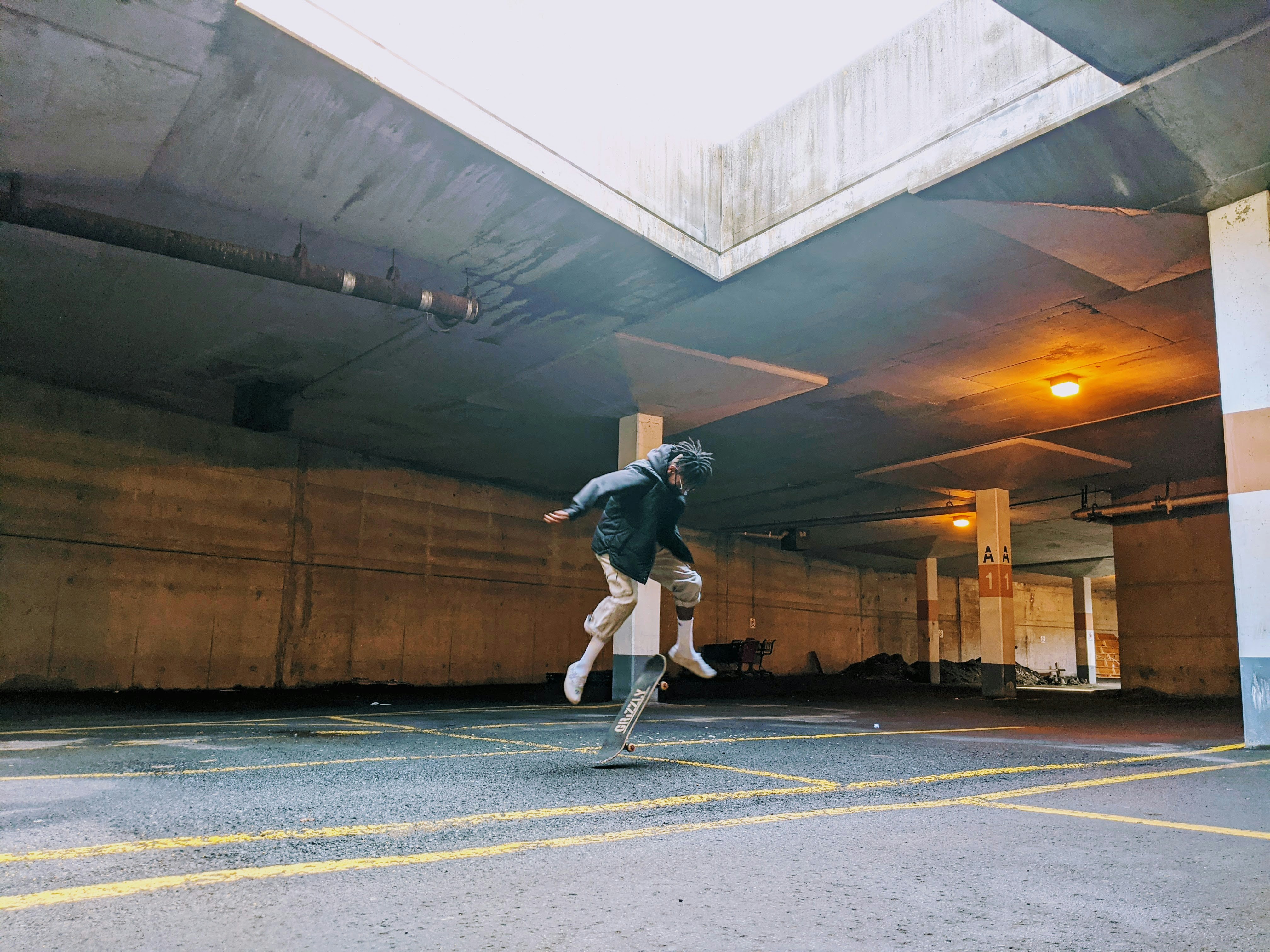 Person jumping energetically in a dimly lit parking garage with a warm overhead light.