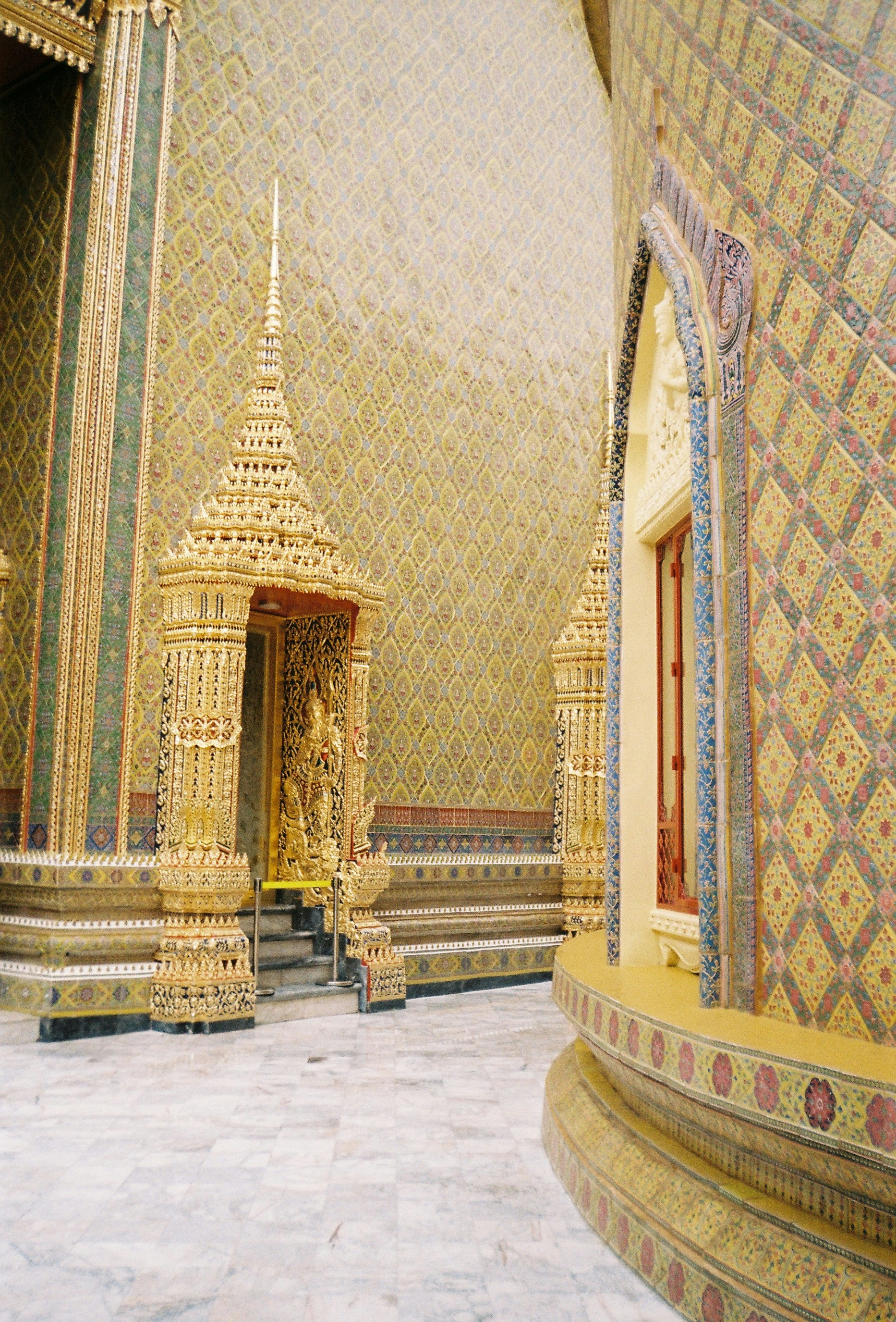 Elaborate golden architecture framed by vibrant patterned walls in a temple setting.