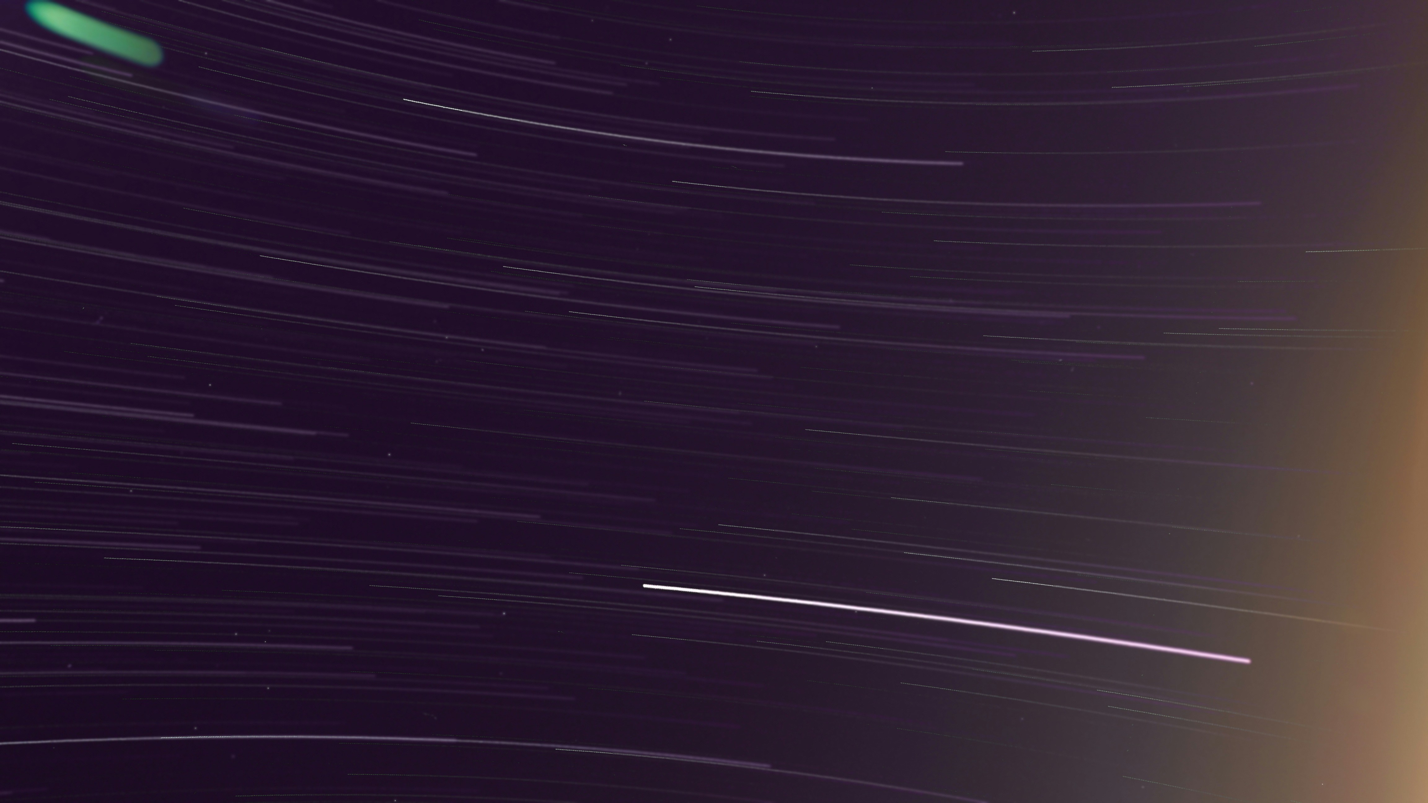 Long exposure capturing the trails of stars against a deep night sky with a hint of color variation. A glimpse into the cosmos' rhythmic motion.