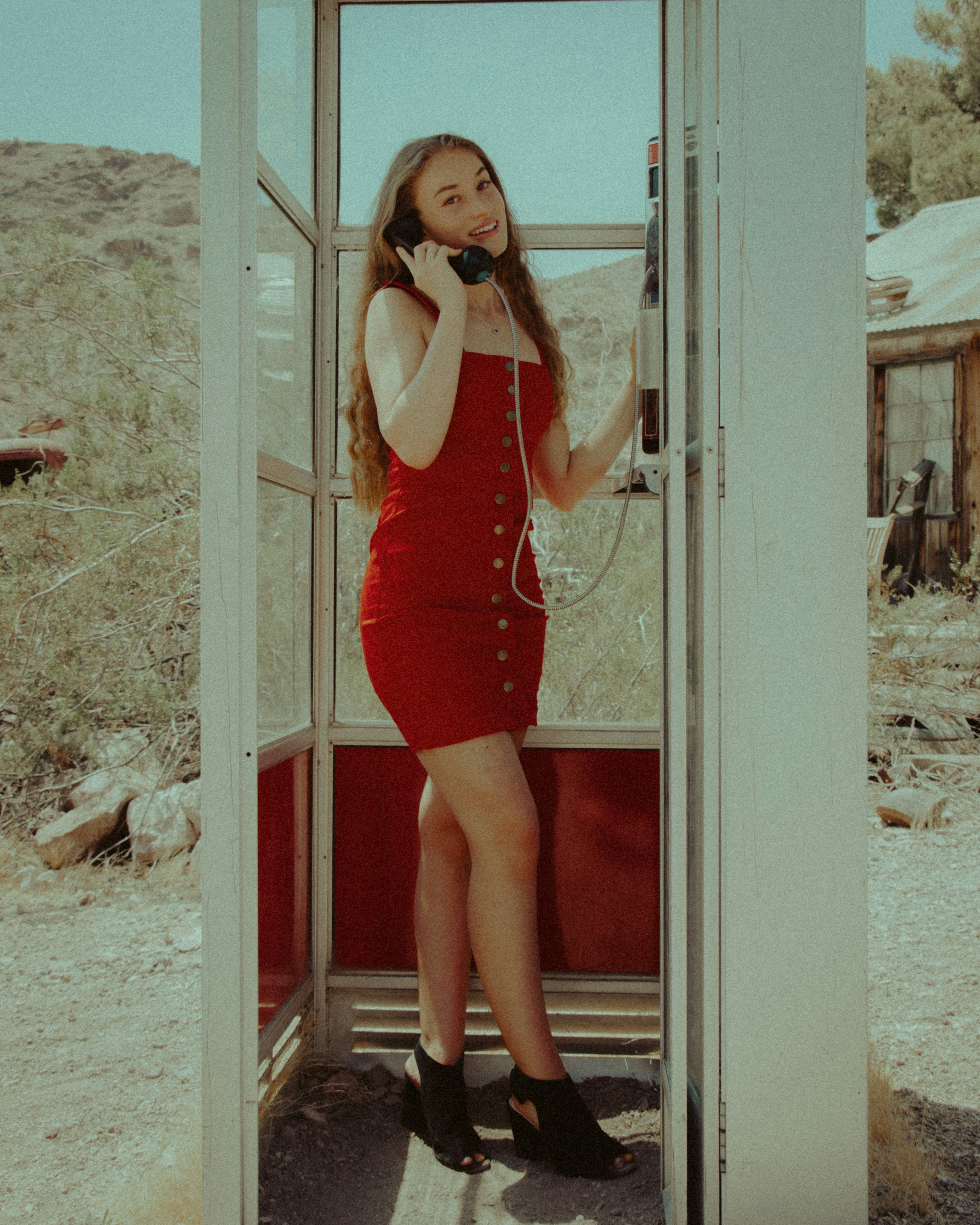 Red Dress in the Telephone Booth: A Moment of Quiet Confidence