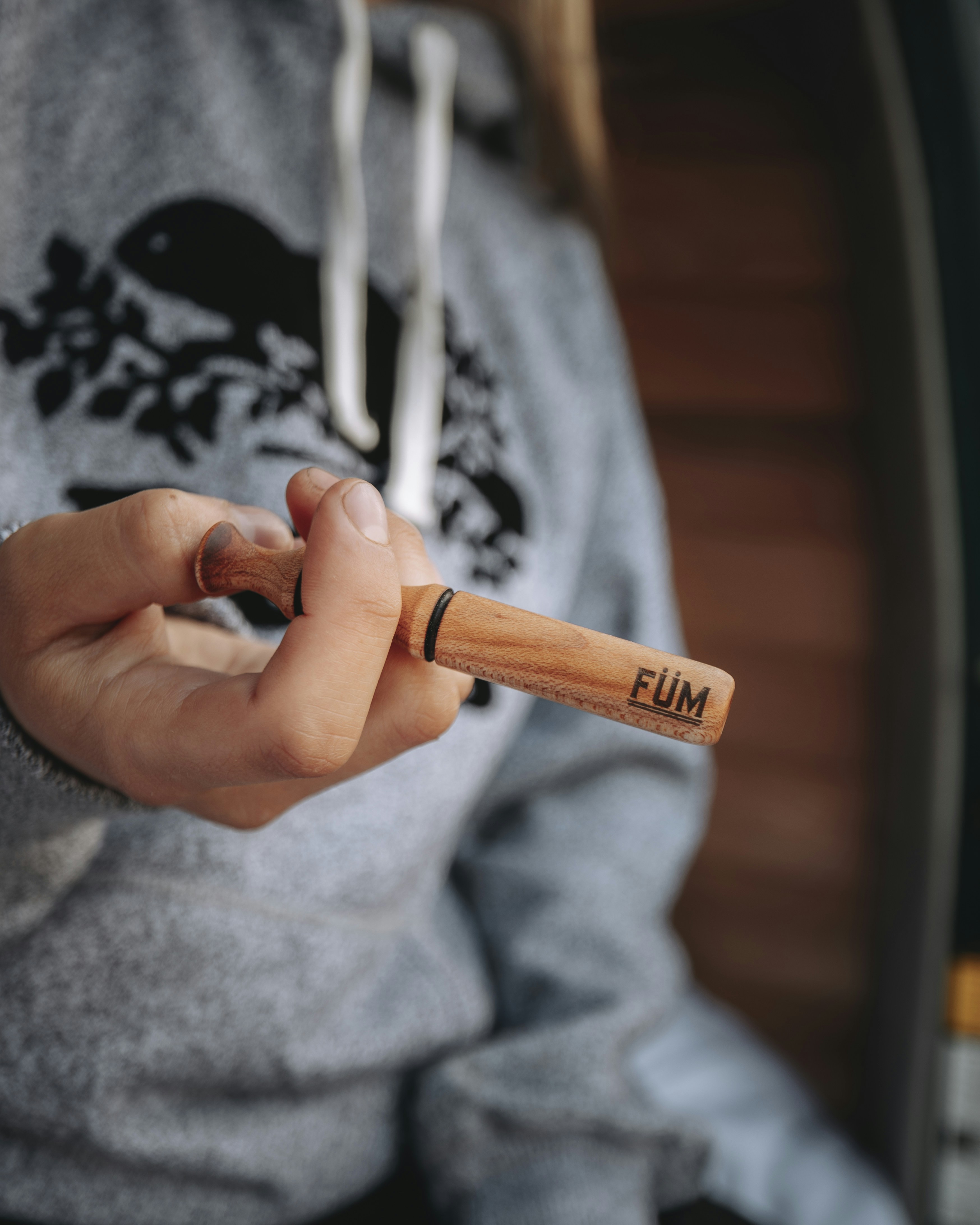 Grip of Craft: Hoodie-Clad Hand Holds a FUM-Stamped Wooden Token