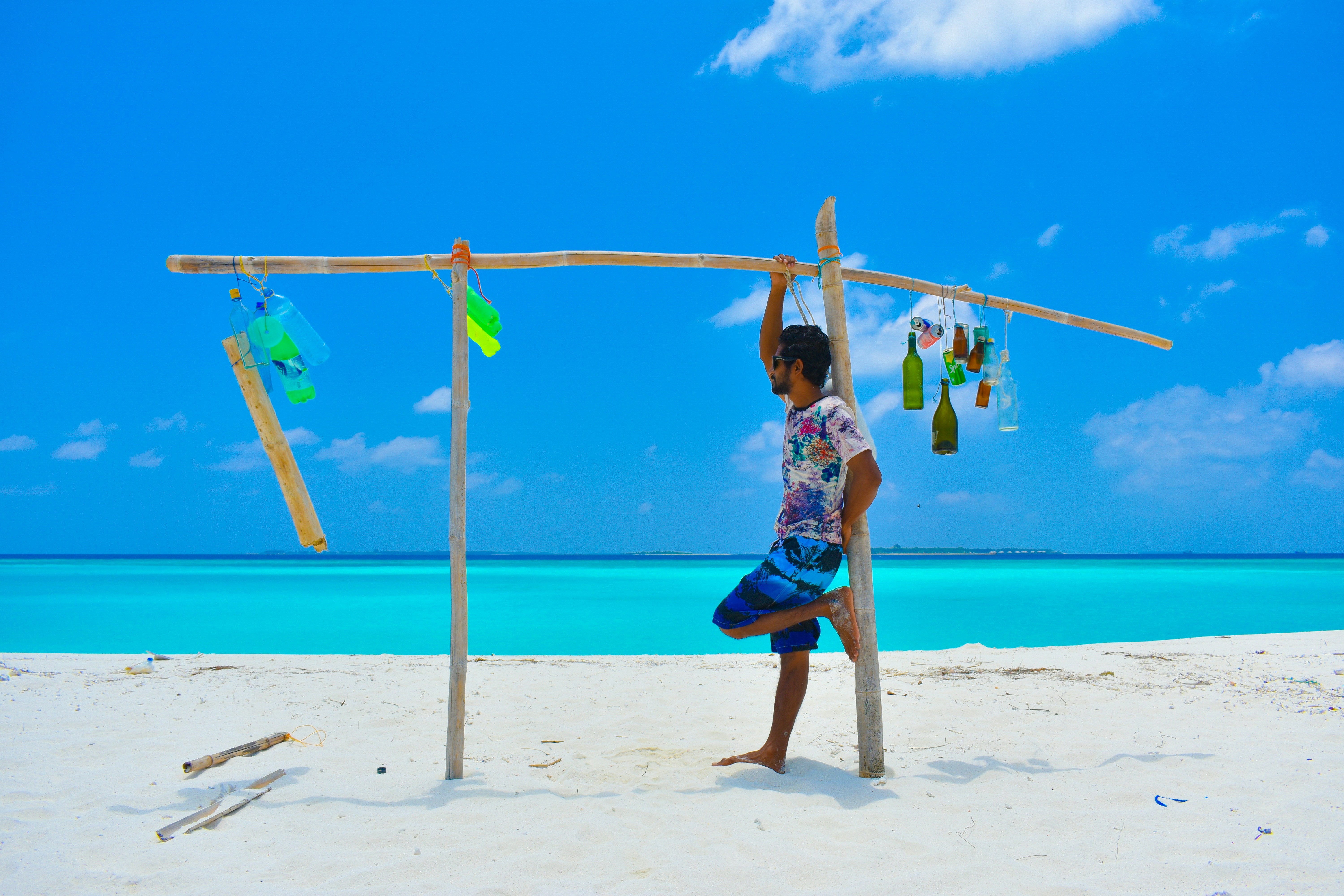 Cantilevered Shade: a barefoot vendor rests beneath a driftwood frame on a turquoise shore
