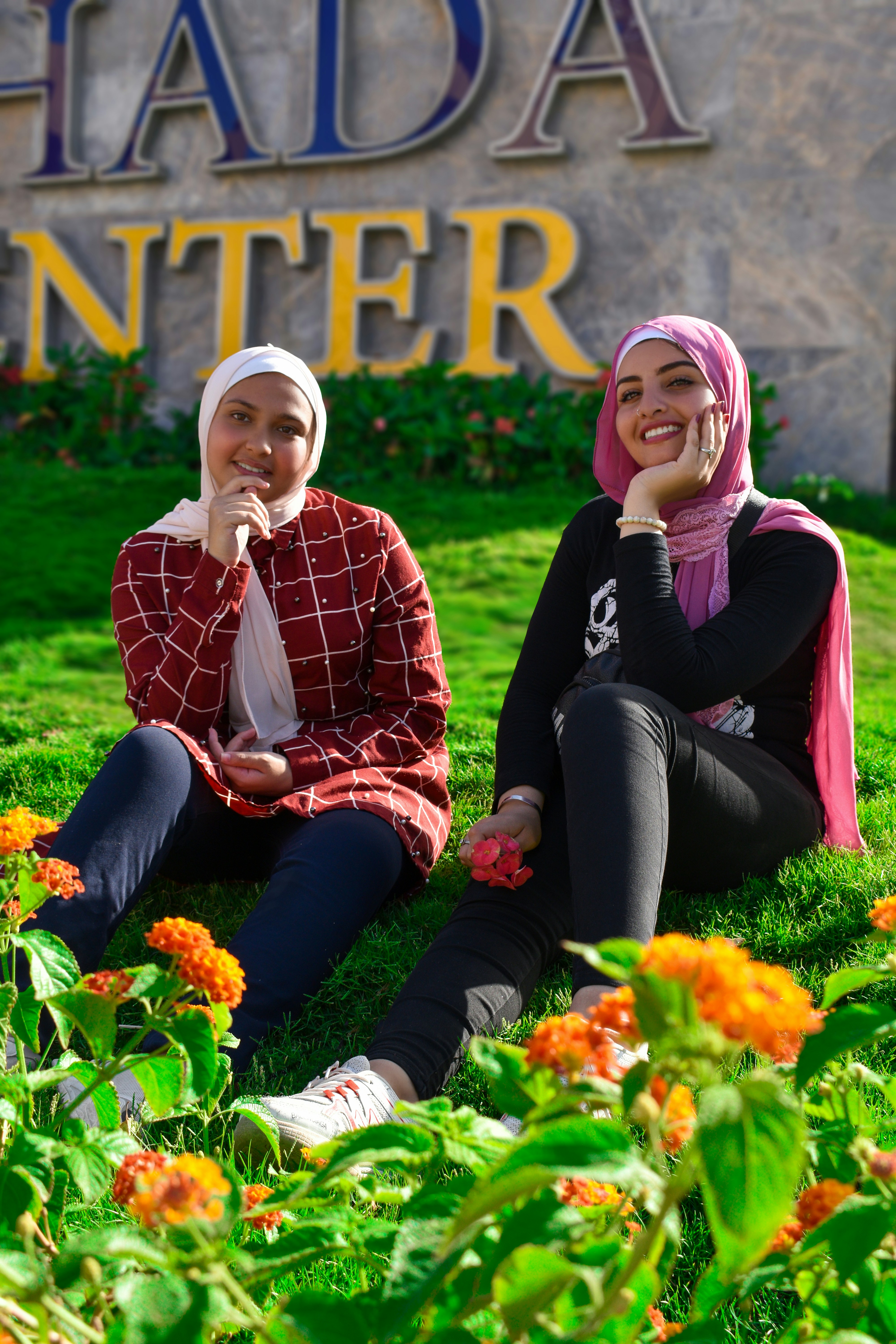 2 women sitting on green grass field