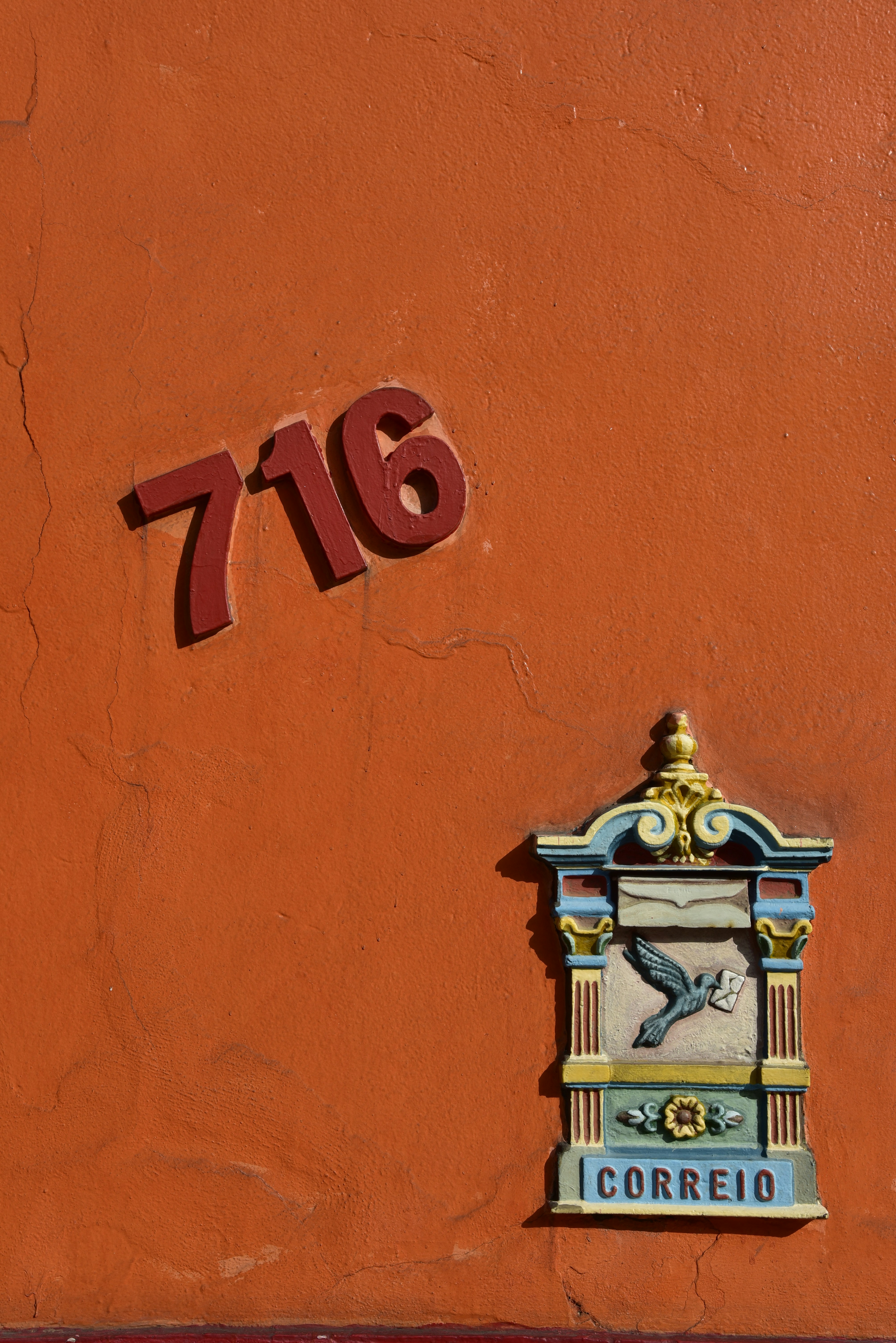Terracotta Wall Portrait: The Ornate CORREIO Mailbox Beneath a Leaning 716