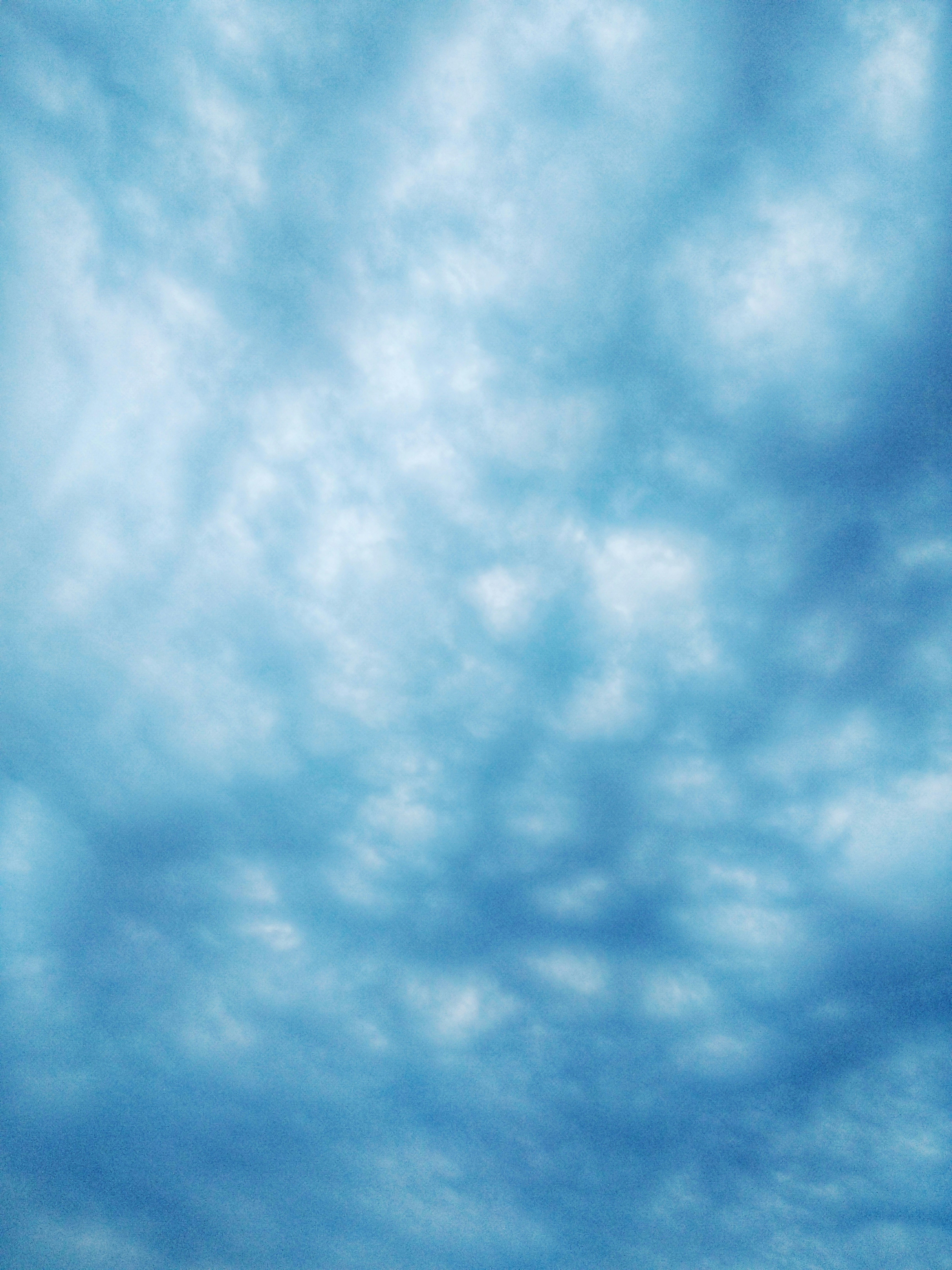 A textured expanse of clouds drifting across a blue sky, creating a serene and atmospheric scene.