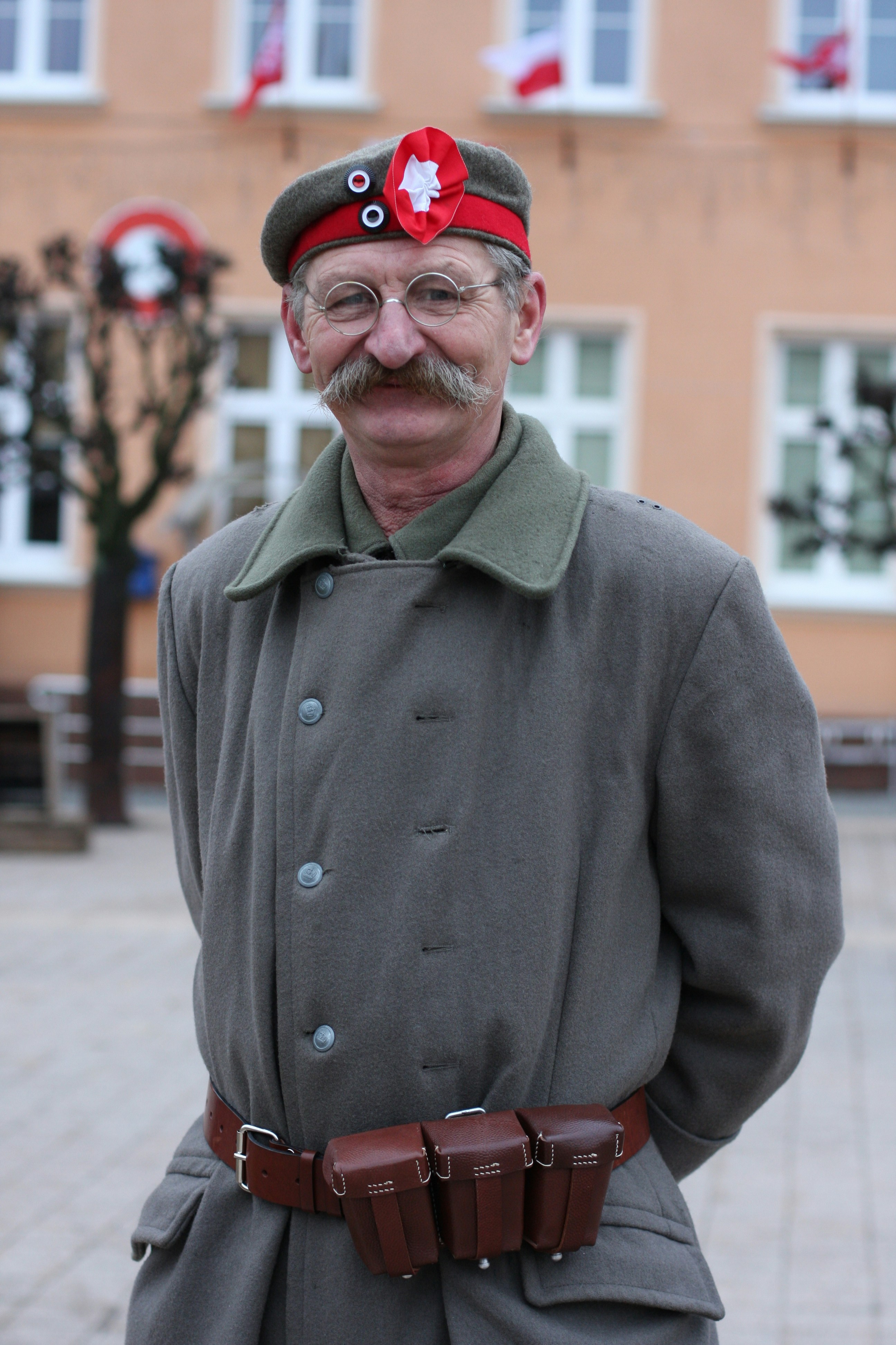 Man in green coat wearing red cap standing on street during daytime ...