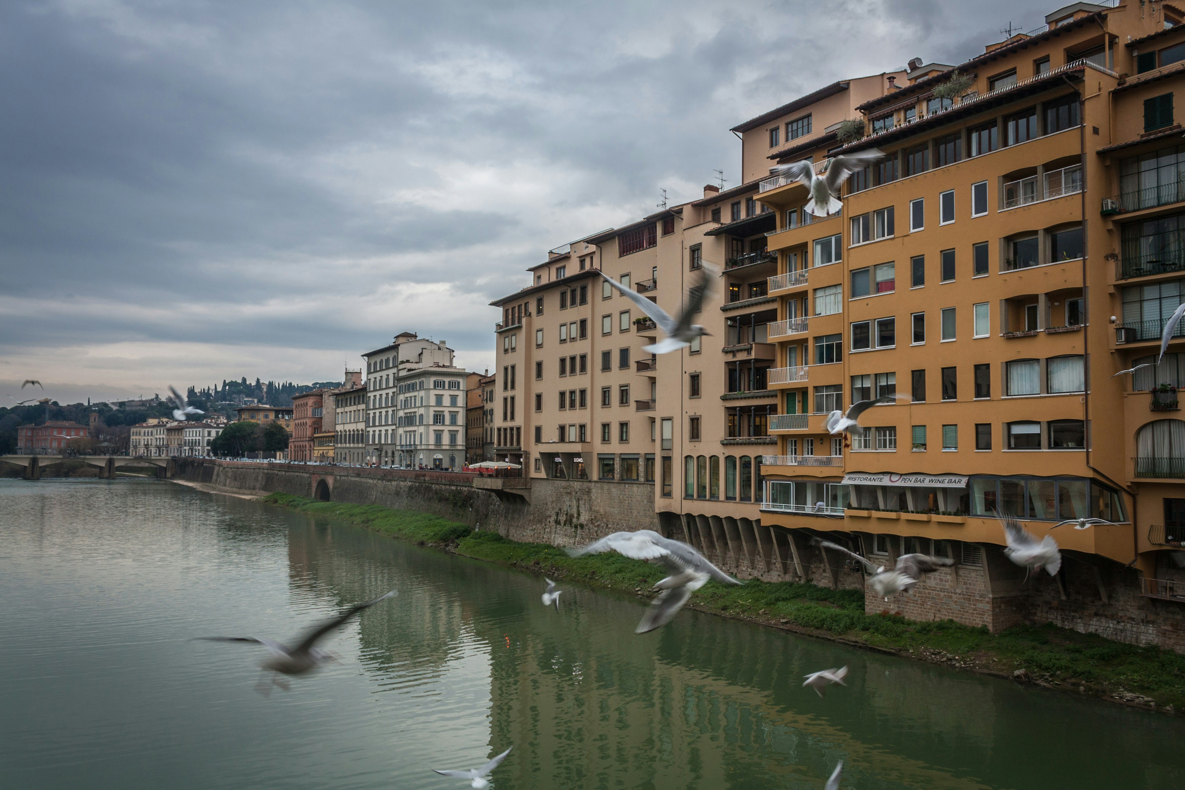 brown and white concrete buildings beside river under white clouds during daytime