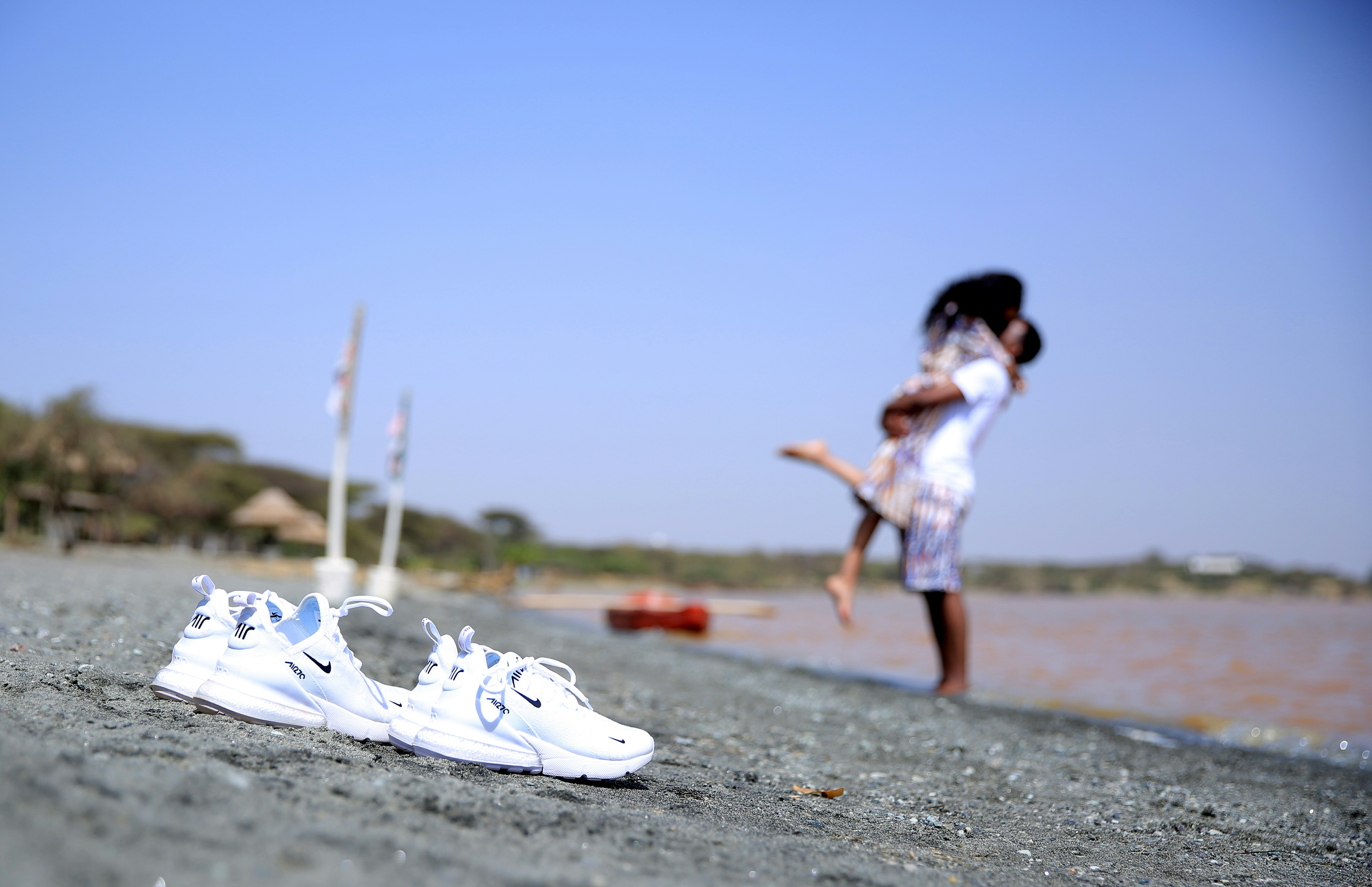 girl in white shirt and blue shorts walking on gray asphalt road during daytime