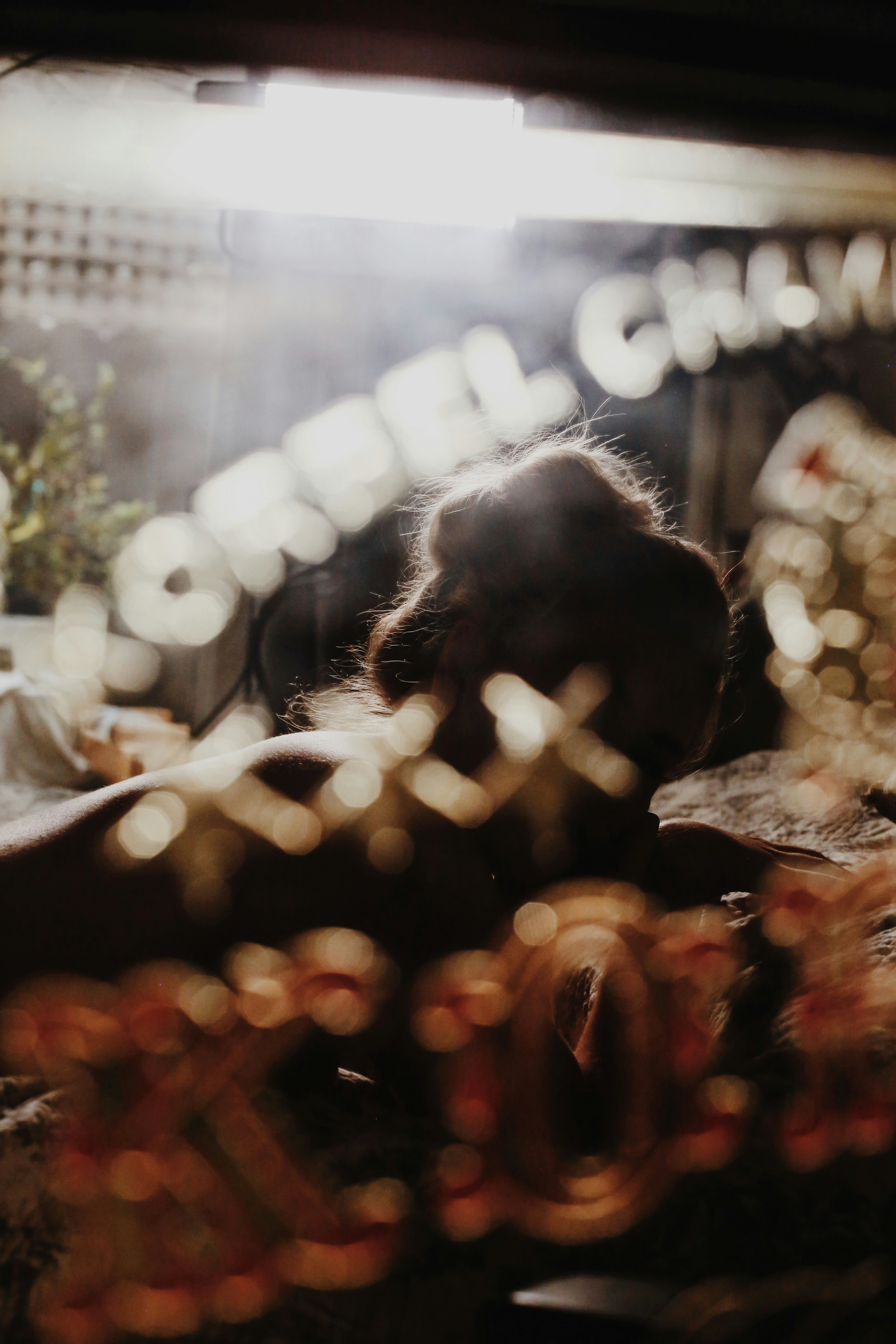 Backlit Reflection: A Quiet Silhouette Woven Through Warm Glass Bokeh