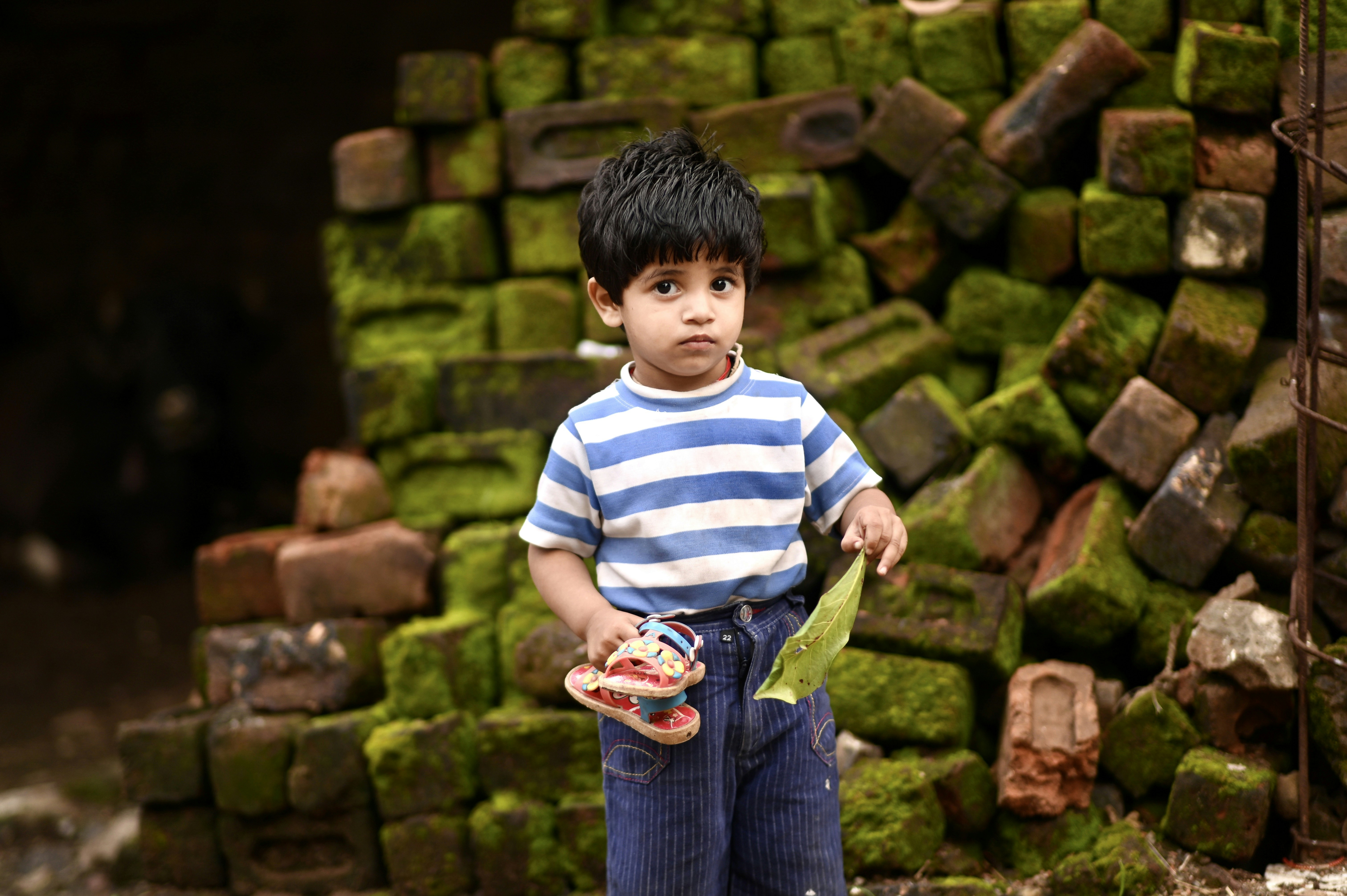 Stripes and Moss: A Quiet Portrait Before a Moss-Covered Brick Wall